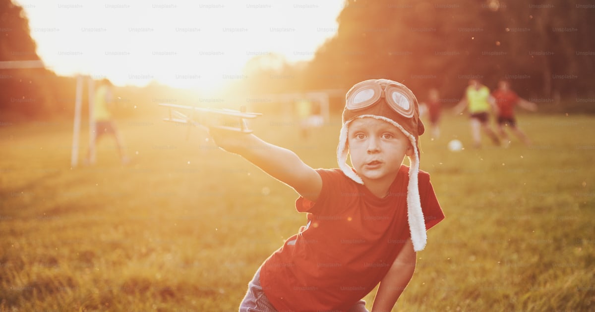 Enfant Heureux Dans Un Casque De Pilote Jouant Avec Un Avion Jouet En