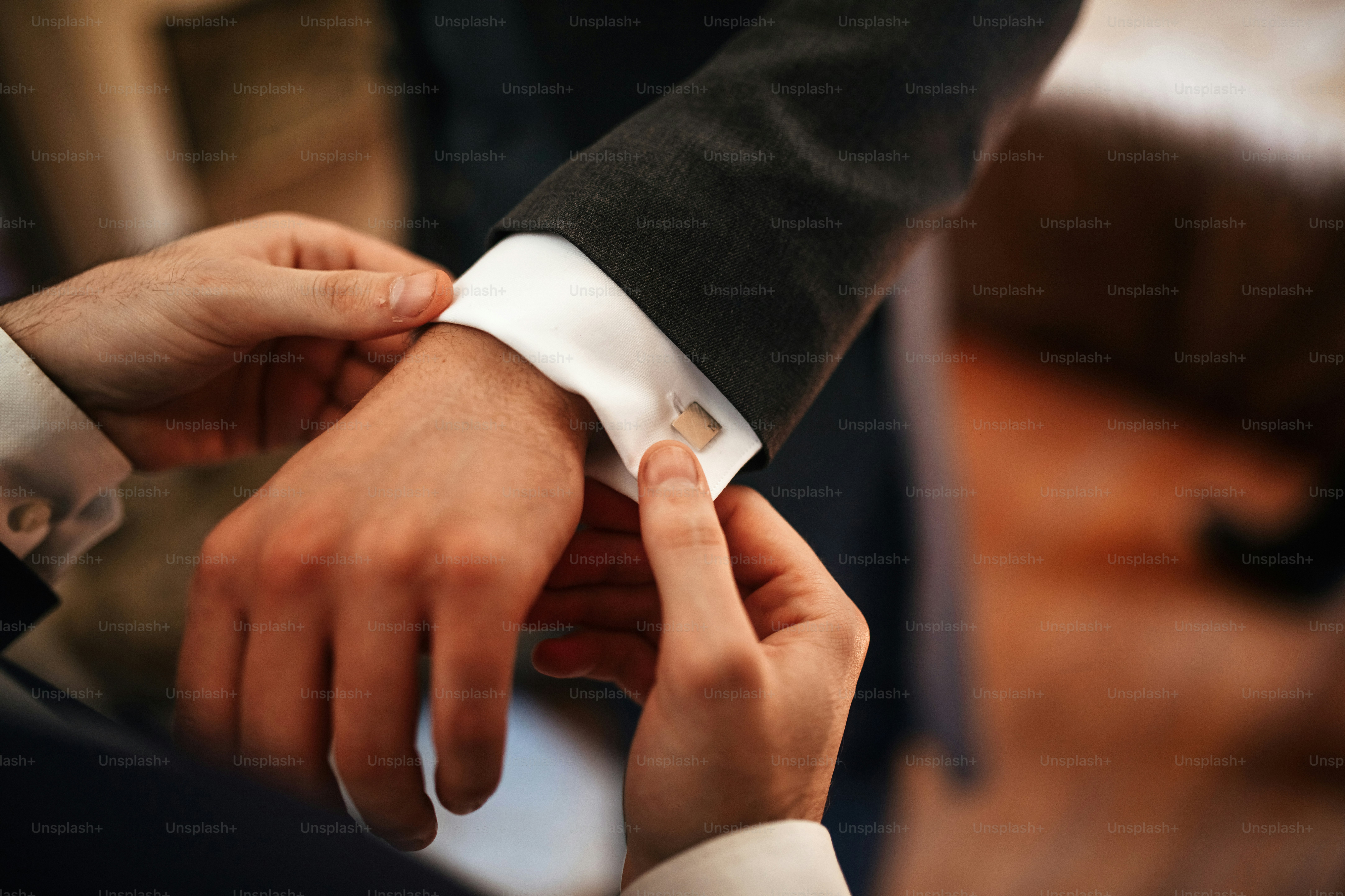 Close up of man helping groom to adjust his suit sleeves on his wedding ...