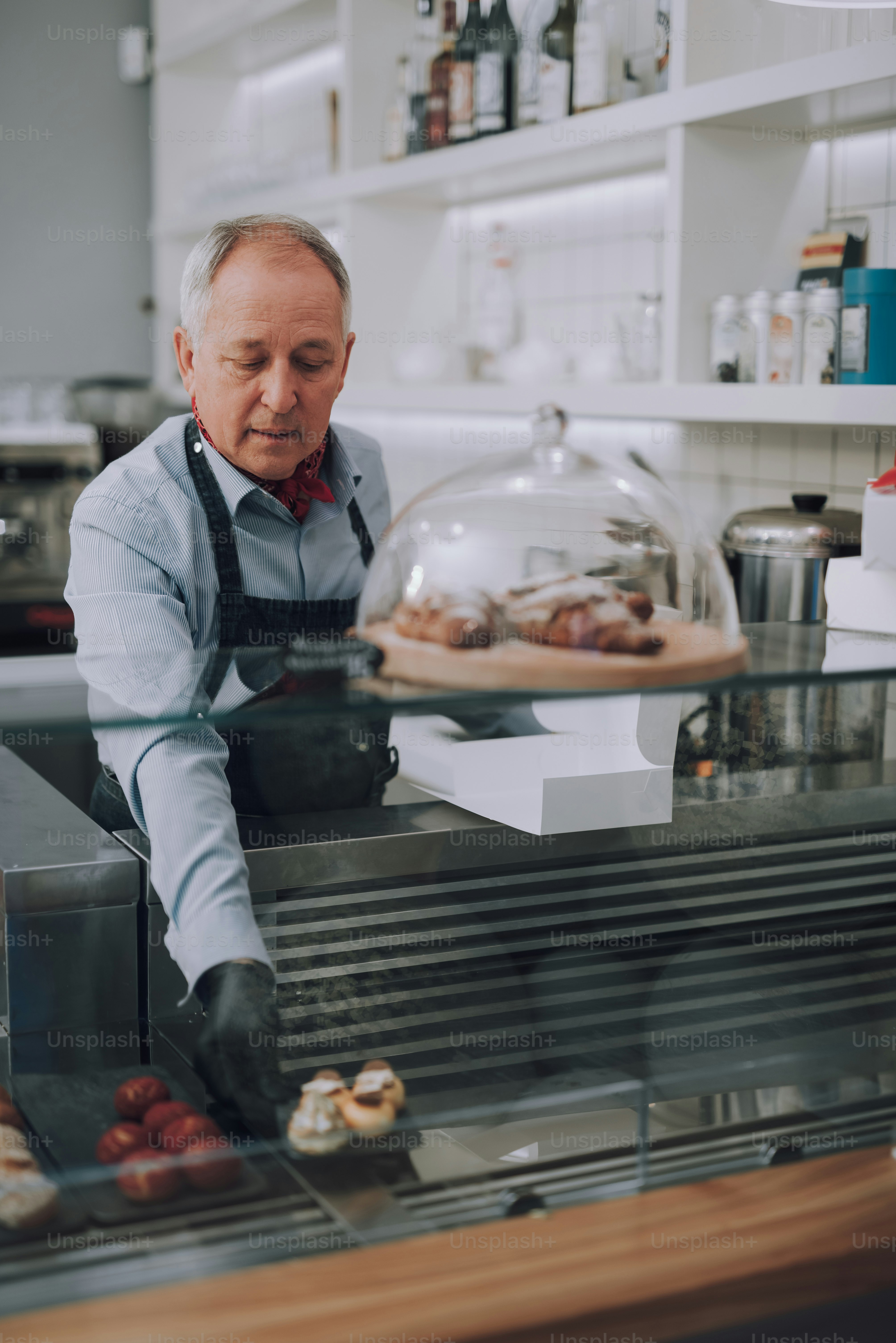 Vertical portrait of good-looking gentleman in apron placing cakes on ...