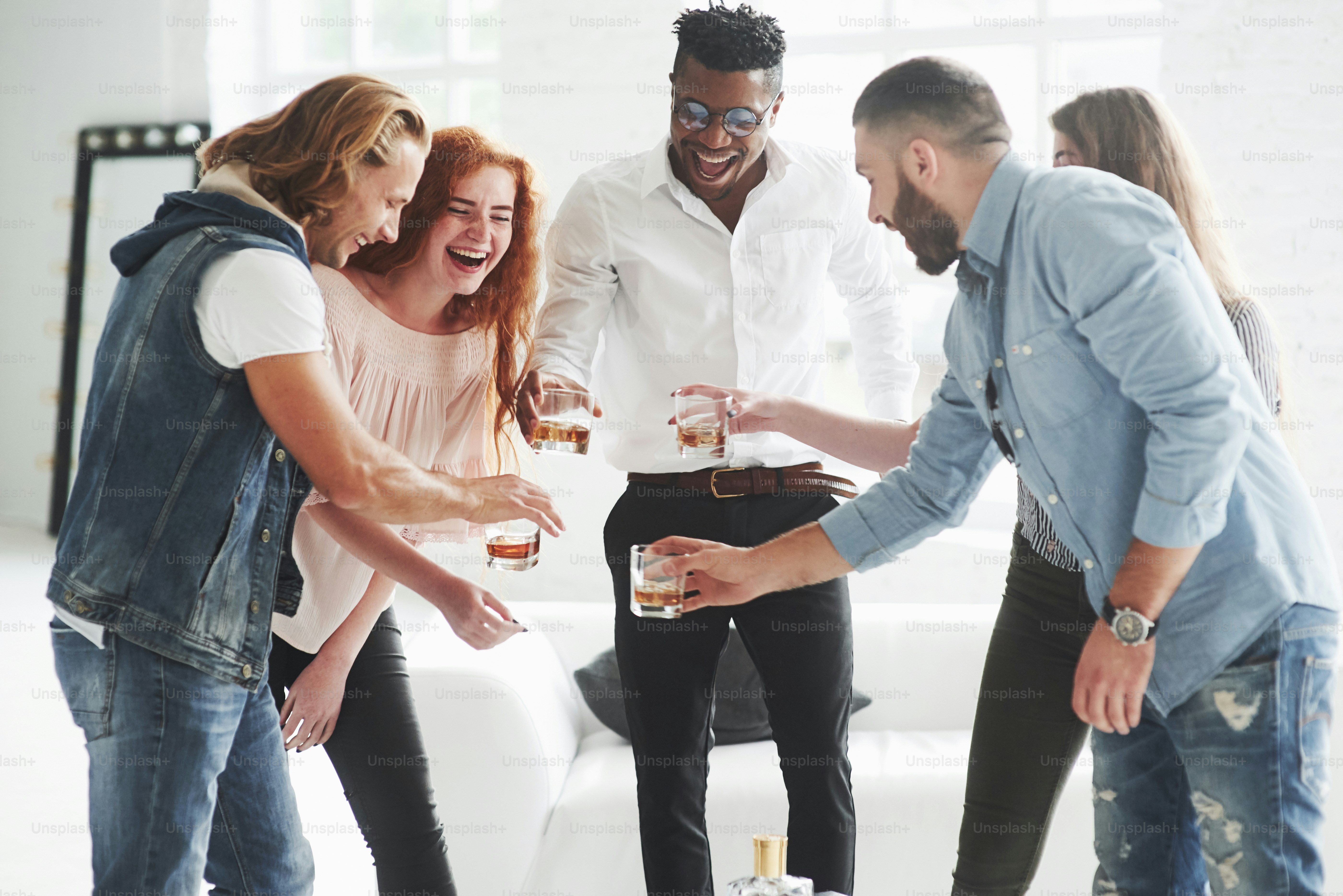 Celebration of team success. Teammates drinking whiskey and laughing ...