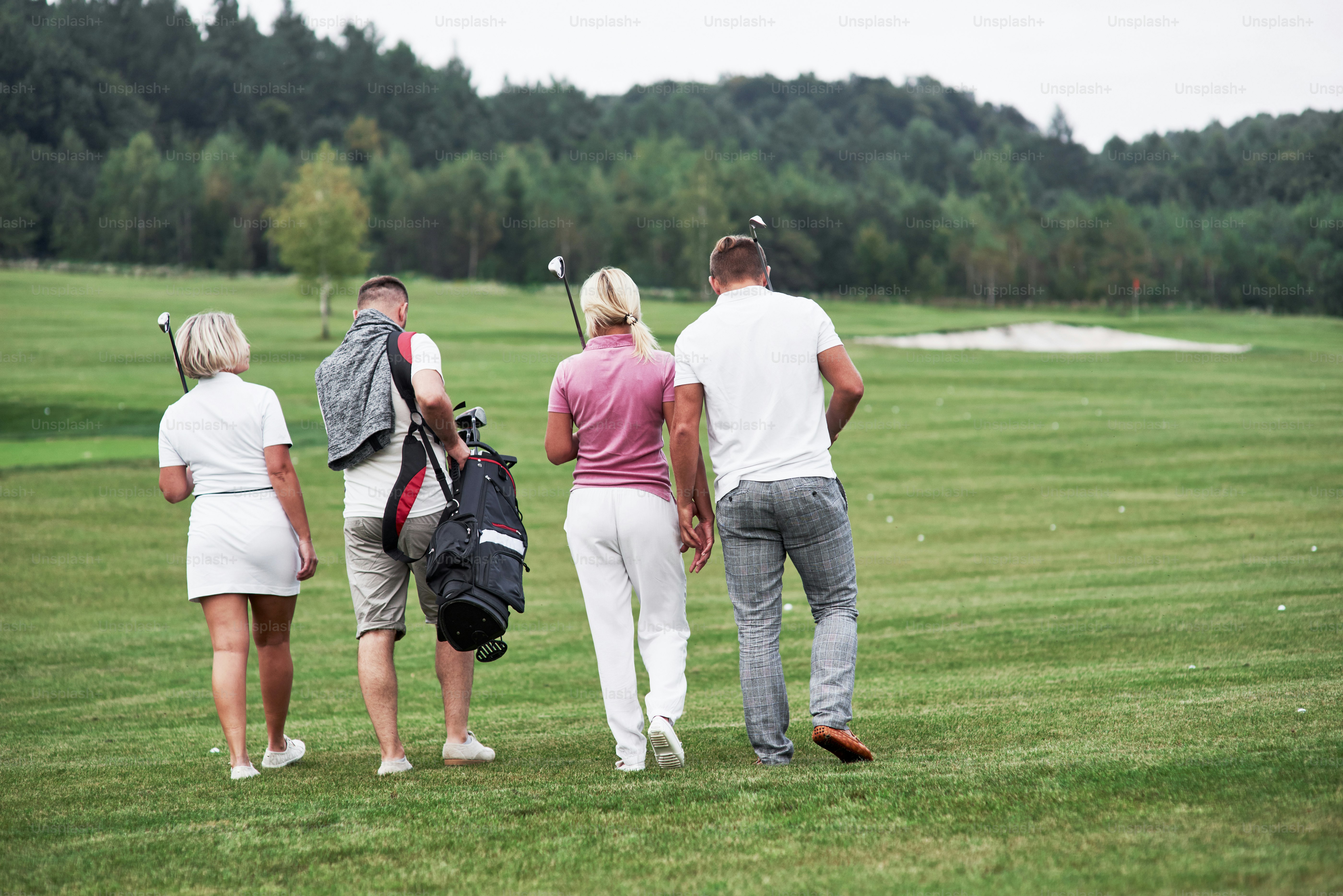 Photo of friends hugging and smiling with golf equipment after the game ...
