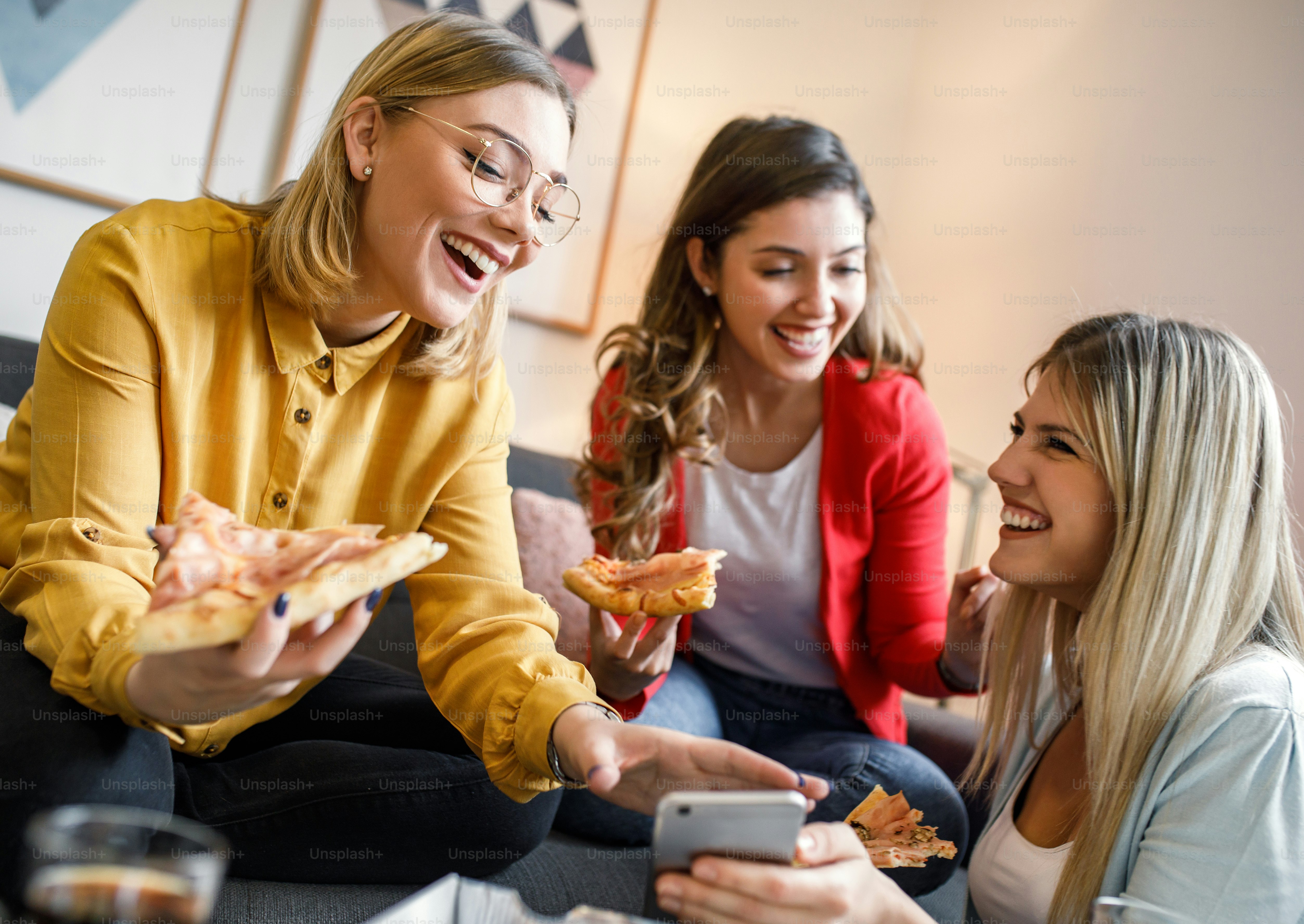 Three female friends chatting and enjoying eating pizza at home. photo ...