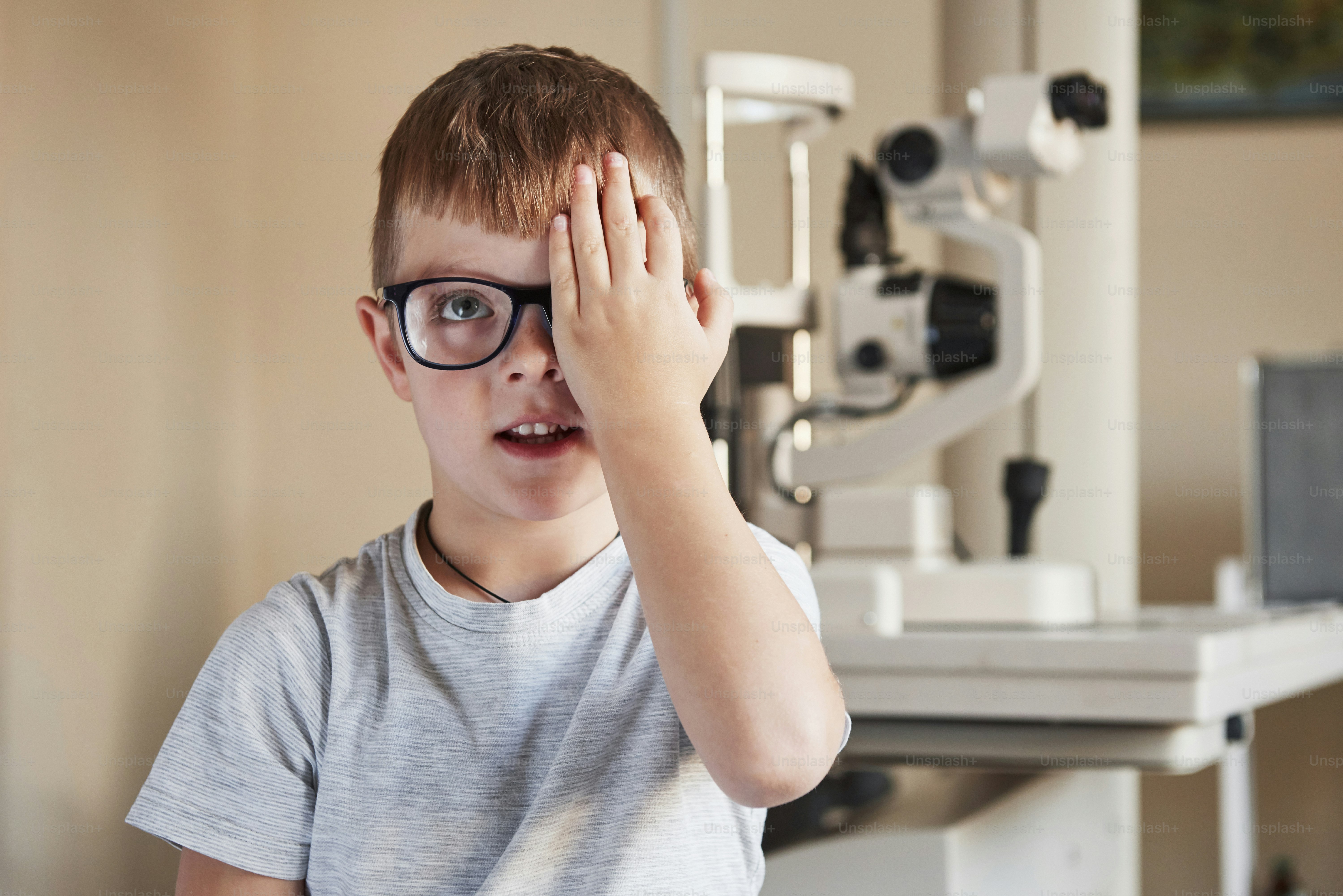 Little boy covering his eye and have reviewing eyesight in the clinic ...