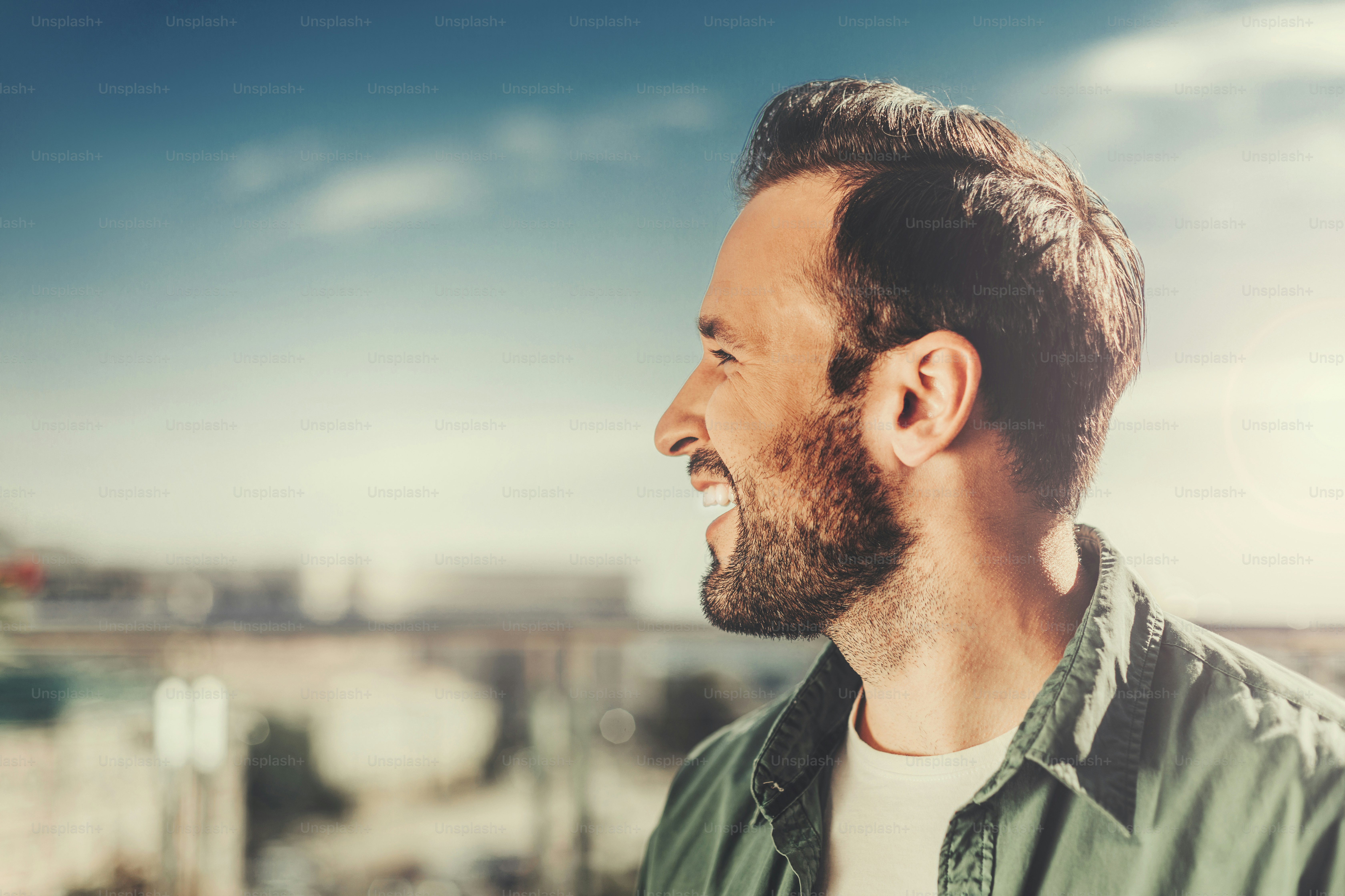Feeling happy. Close up side view of handsome guy looking away and ...