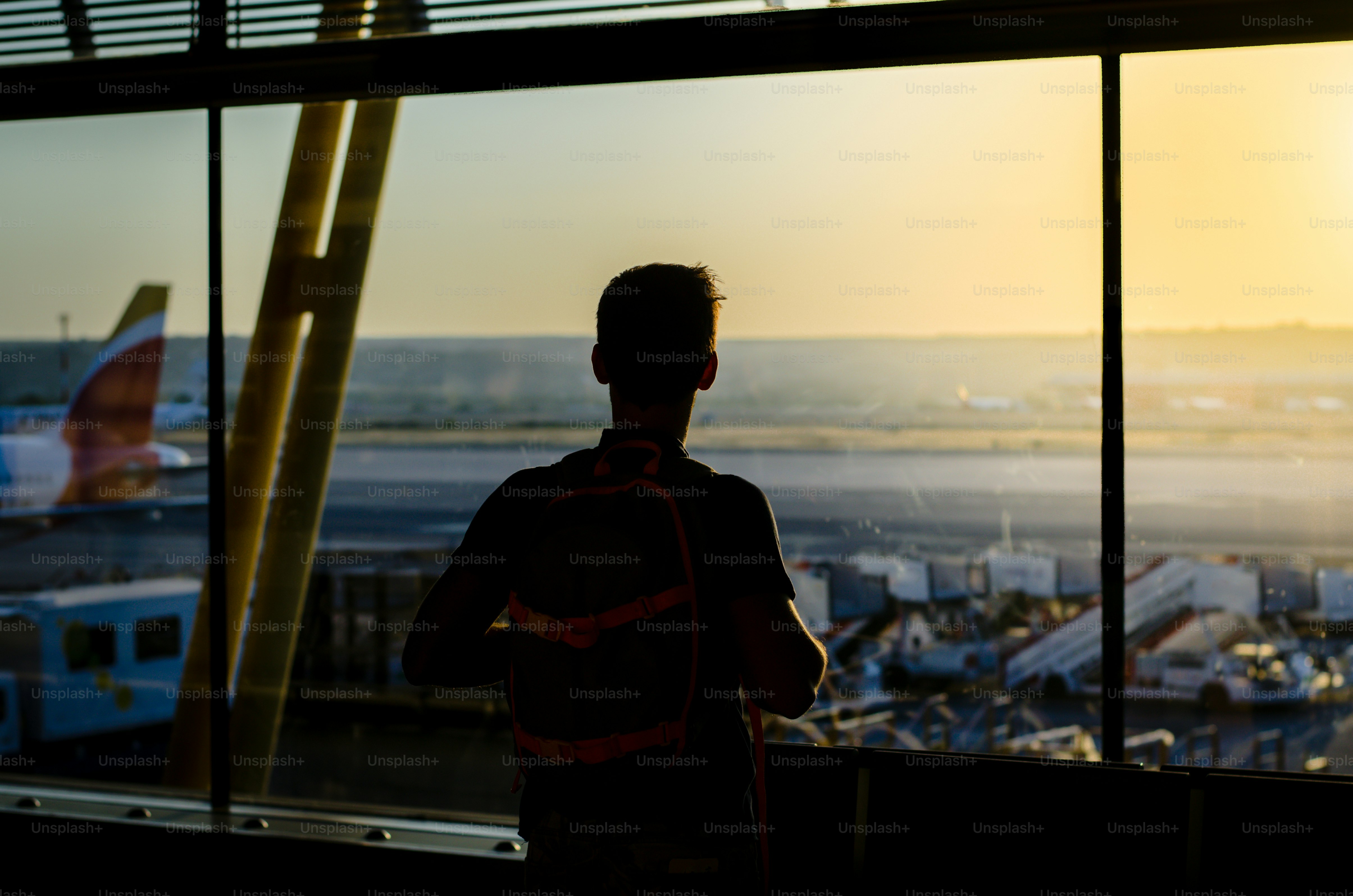 Thoughtful young man looking by the window at a airport terminal photo ...