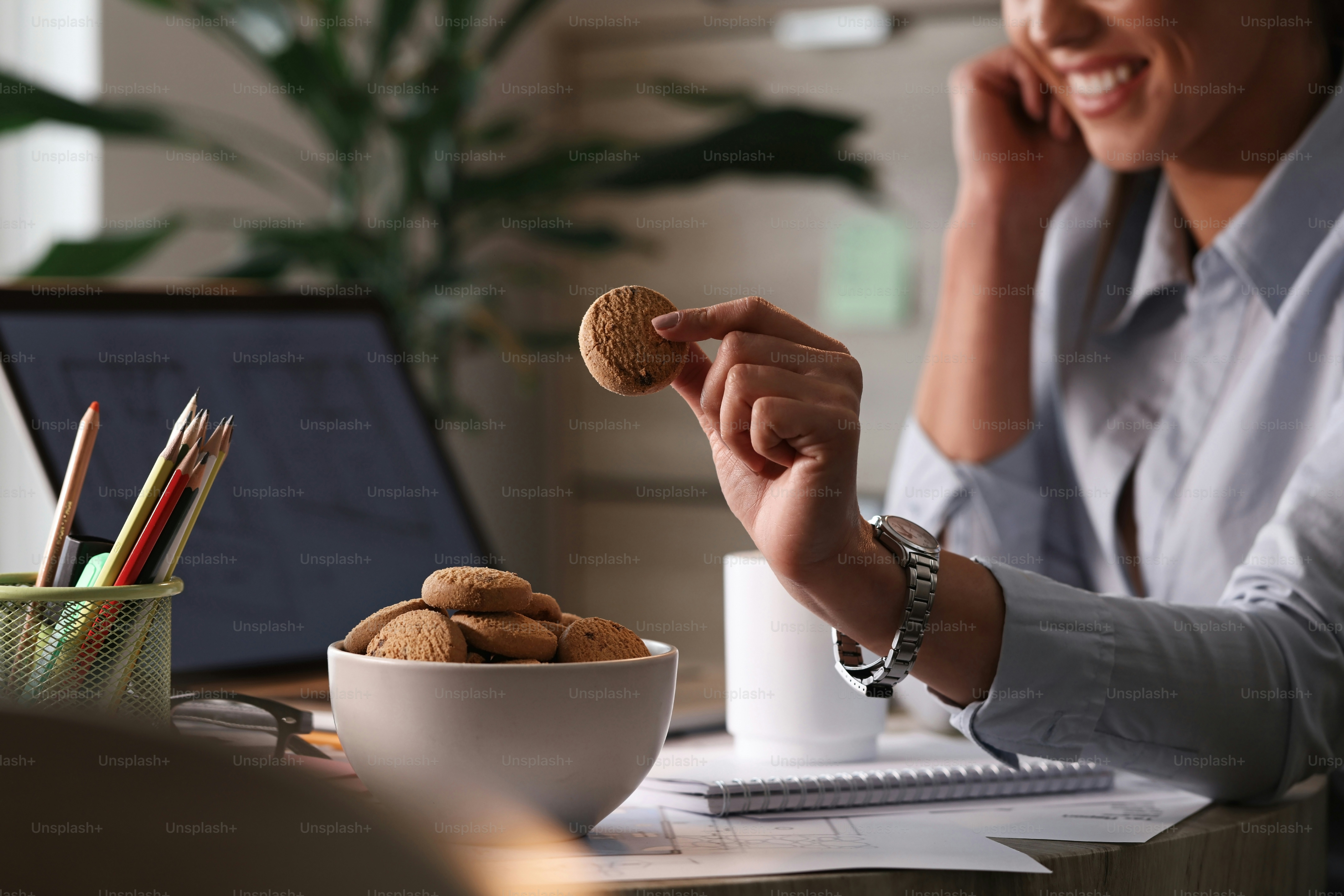Close up of businesswoman eating cookies on a break in her office ...