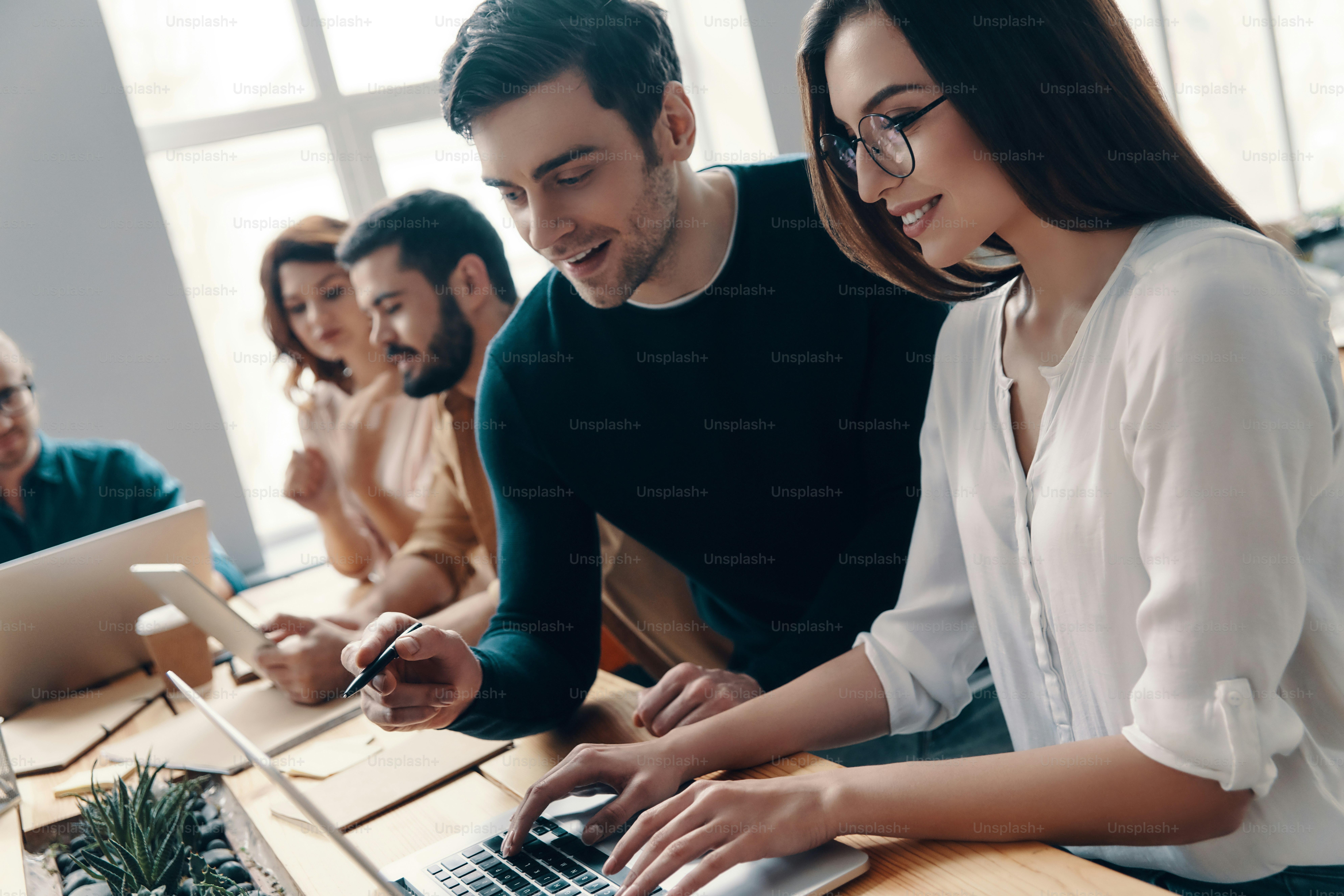 Group of young modern people in smart casual wear using modern ...