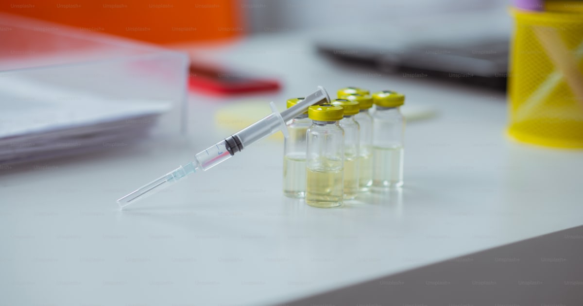 アンプルのシリンジ。医師のテーブルの上に抗生物質が入ったアンプルの上に横たわっている医療用注射器の接写の写真 ヘルスケアと医学