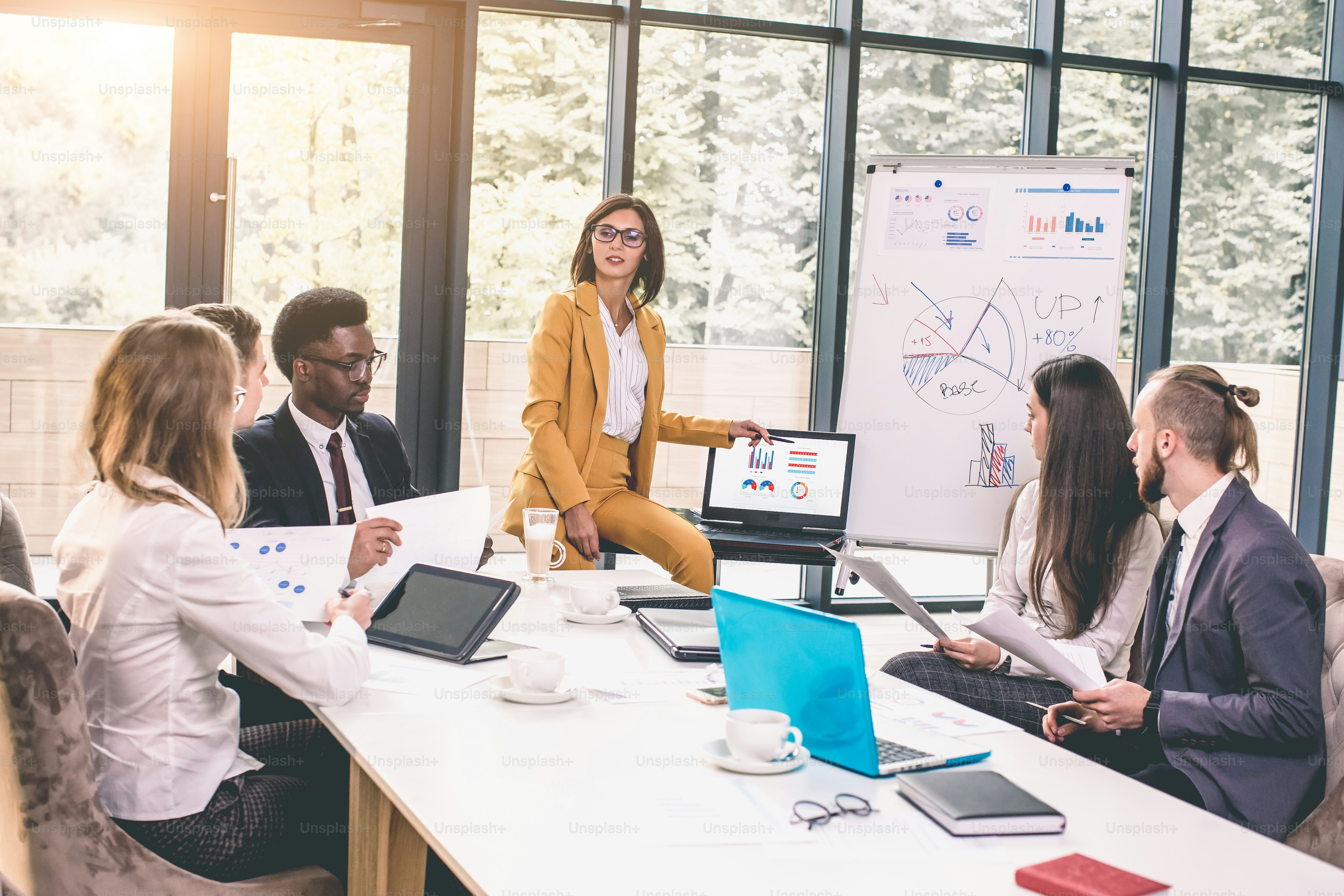 Foto zum Thema Geschäftsfrau steht auf, um Treffen am Vorstandstisch zu ...