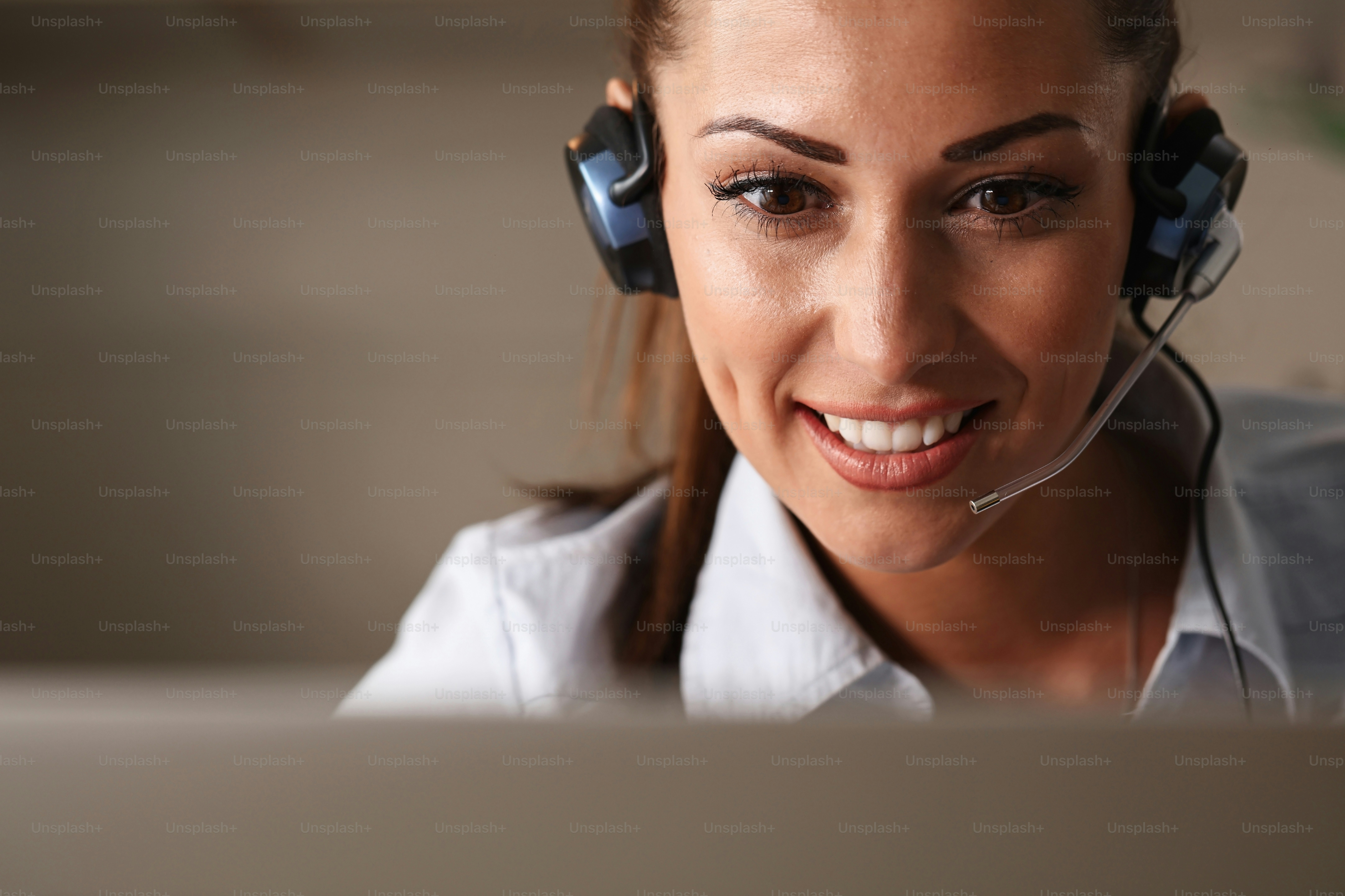 Beautiful smiling call center agent with headset communicating with a ...