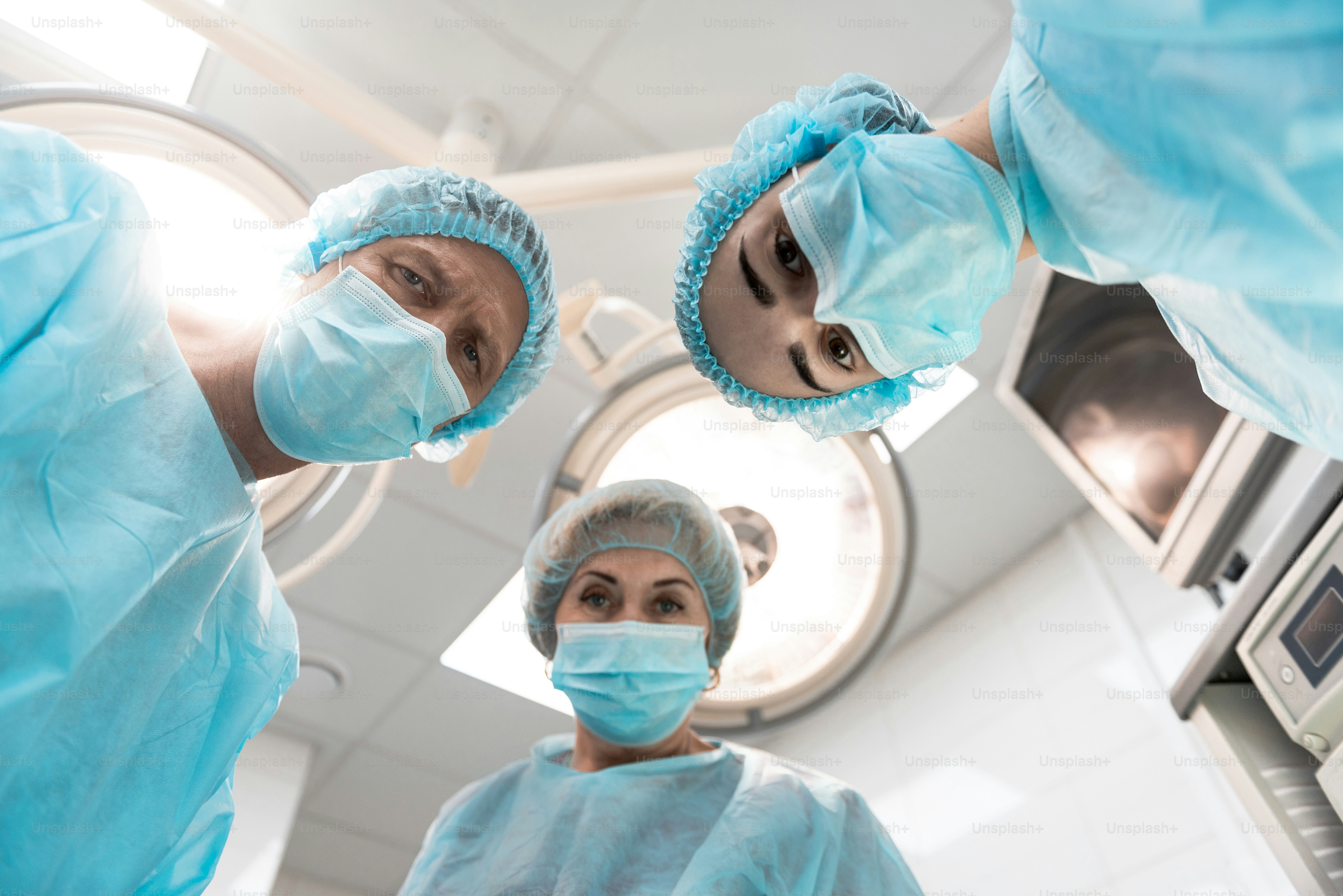 Bottom view of three professional doctors in medical clothes leaning to ...