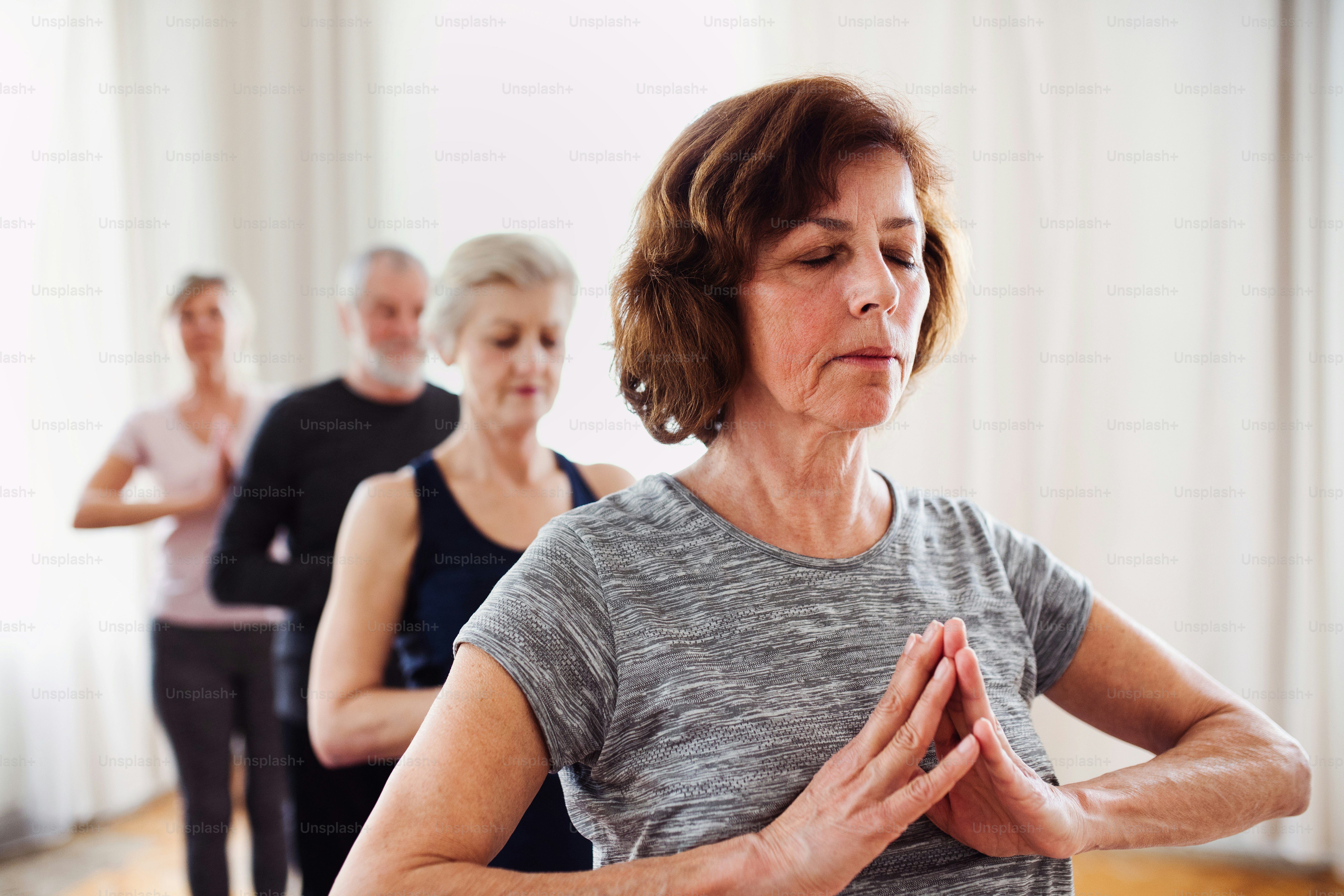 Group of active senior people doing yoga exercise in community center ...