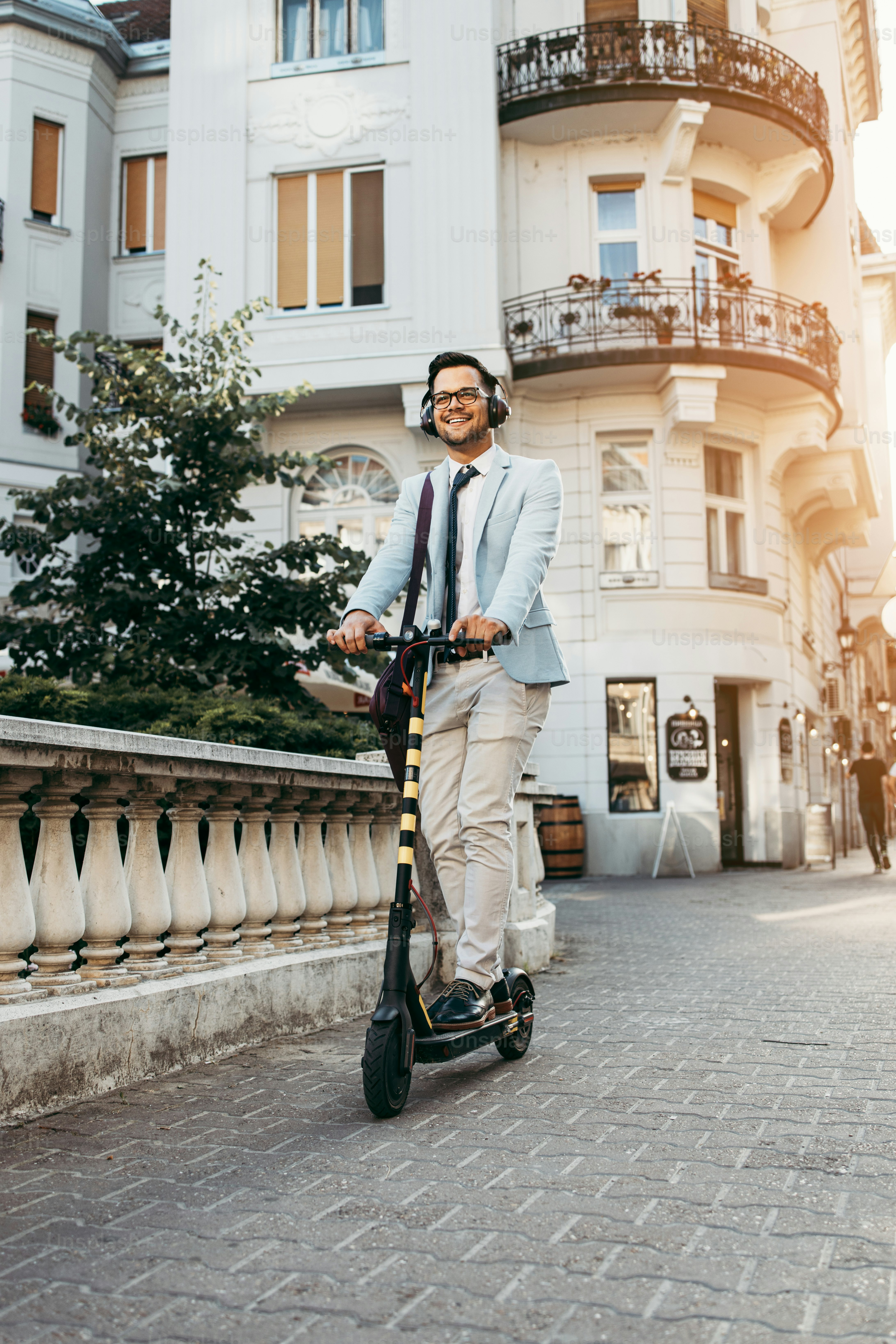 Young modern man using and driving electric scooter on city street ...