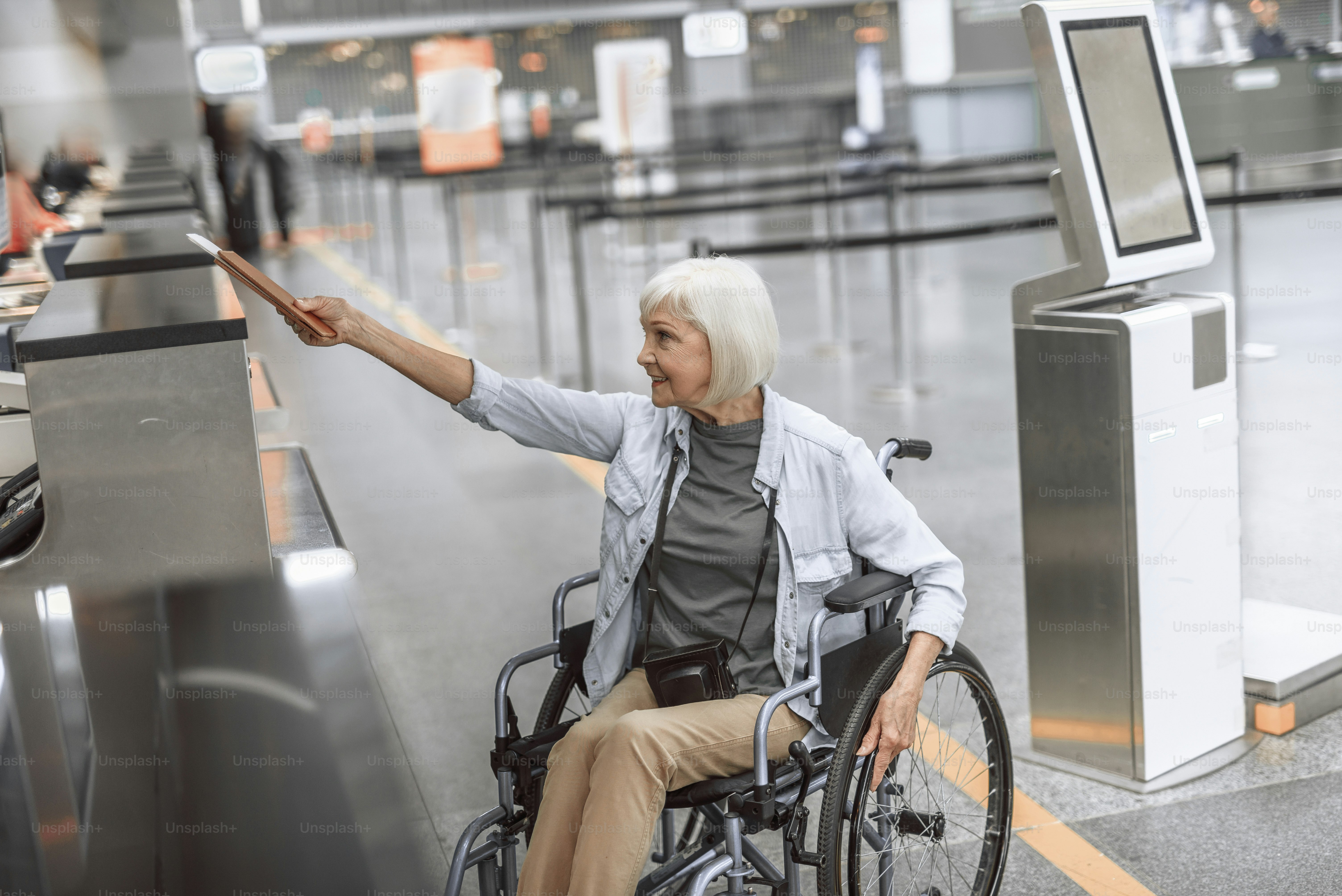 Waist up portrait of smiling old lady with camera sitting in wheelchair ...