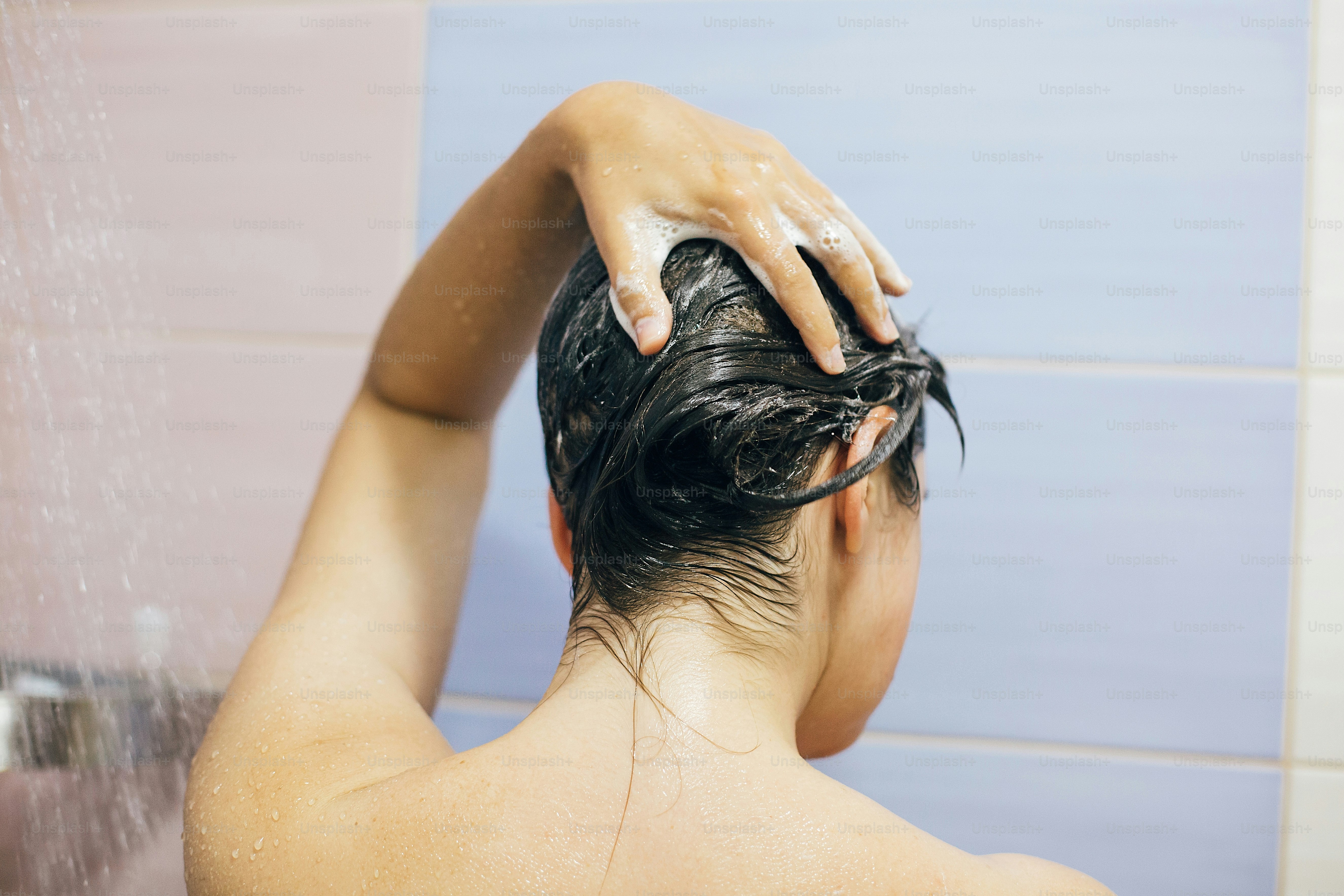 Young happy woman washing her hair with shampoo, hands with foam ...