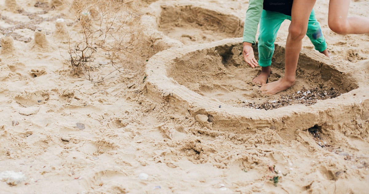 ビーチで砂の城を作る子供たち。幸せな家族と子供たちが砂の上で遊んで、海の近くに砂の城の壁を作ります。夏休みの写真 Unsplashの砦の画像
