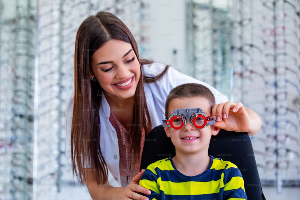 Attractive ophthalmologist examining youg boy with optometrist trial ... Attractive ophthalmologist examining youg boy with optometrist trial ...