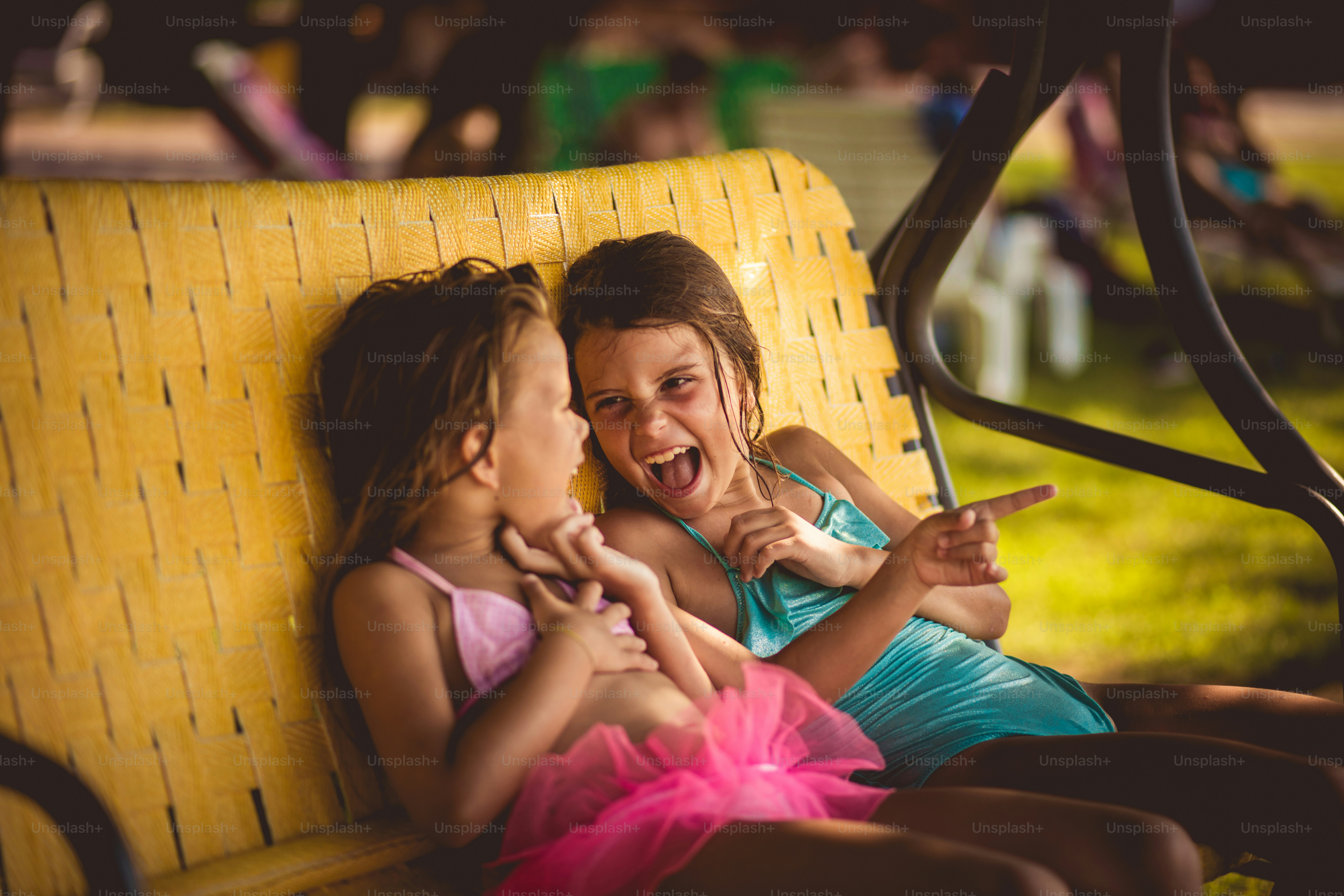 Chatouillement. Deux petites filles assises sur le banc. photo – La ...