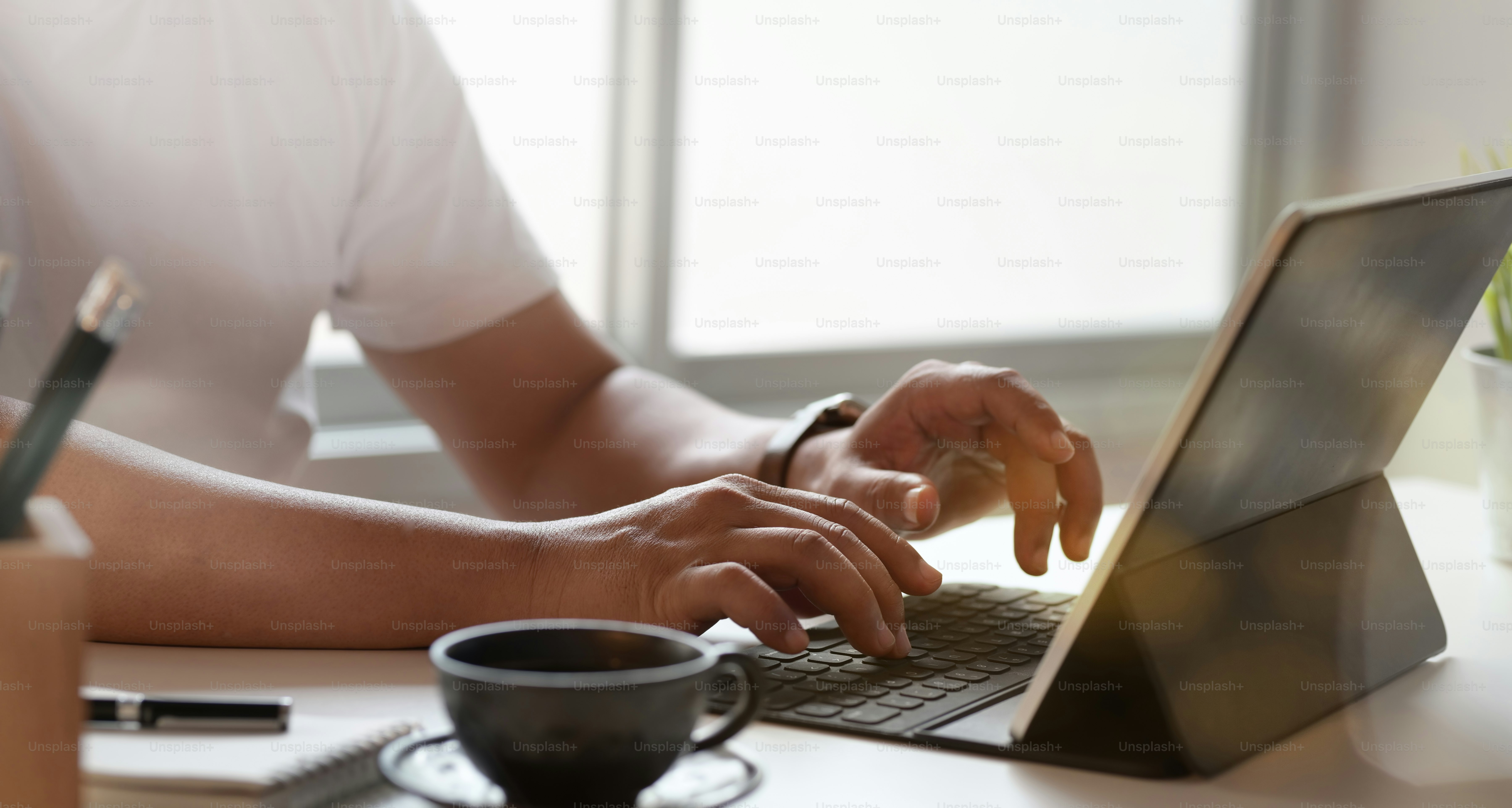 Close-up view of young man typing on keyboard laptop in minimal office ...