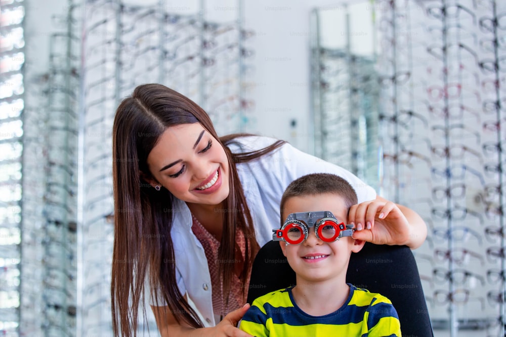 Attractive ophthalmologist examining youg boy with optometrist trial ... Attractive ophthalmologist examining youg boy with optometrist trial ...