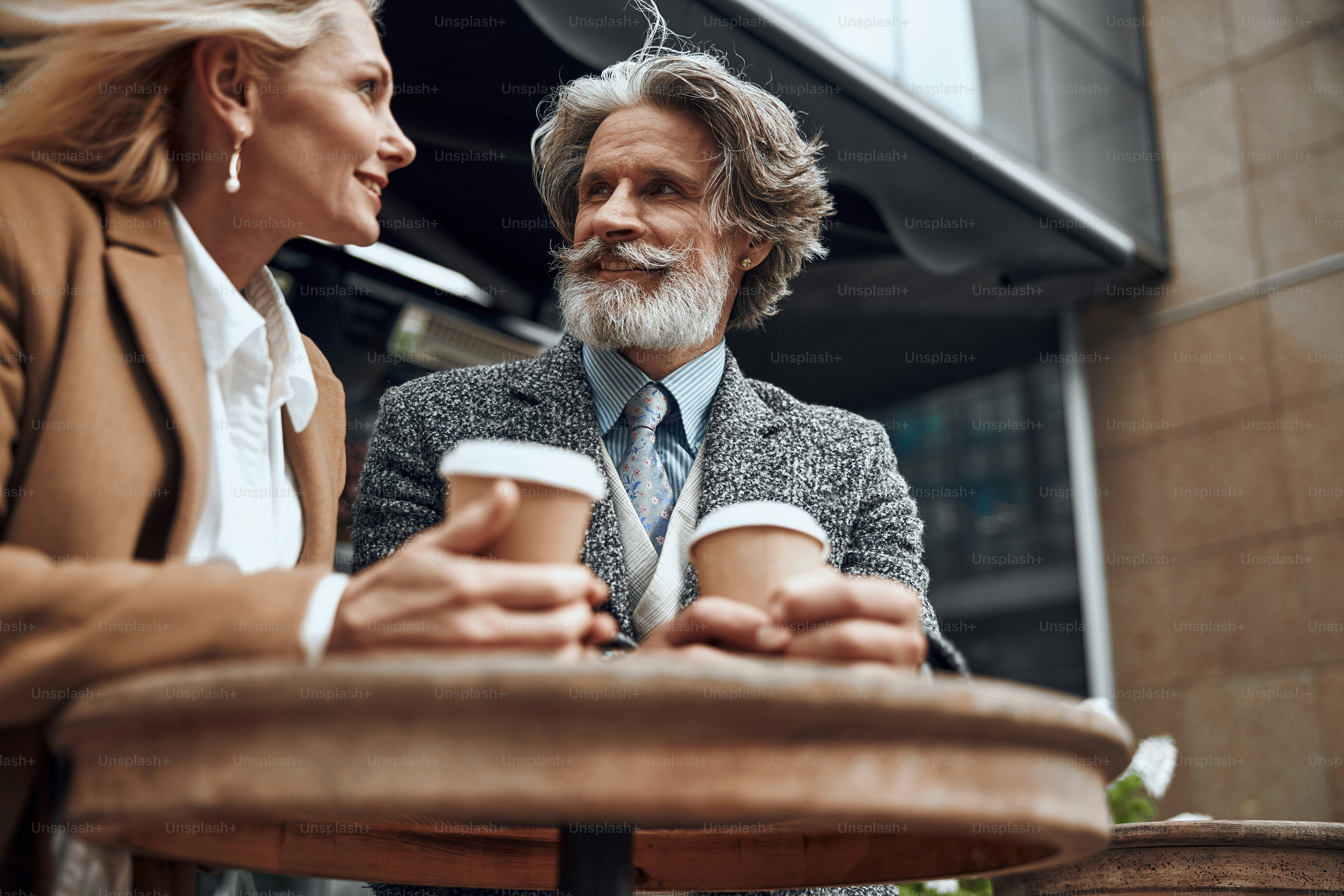 Happy bearded man with coffee to go kindly smiling to a woman next to ...