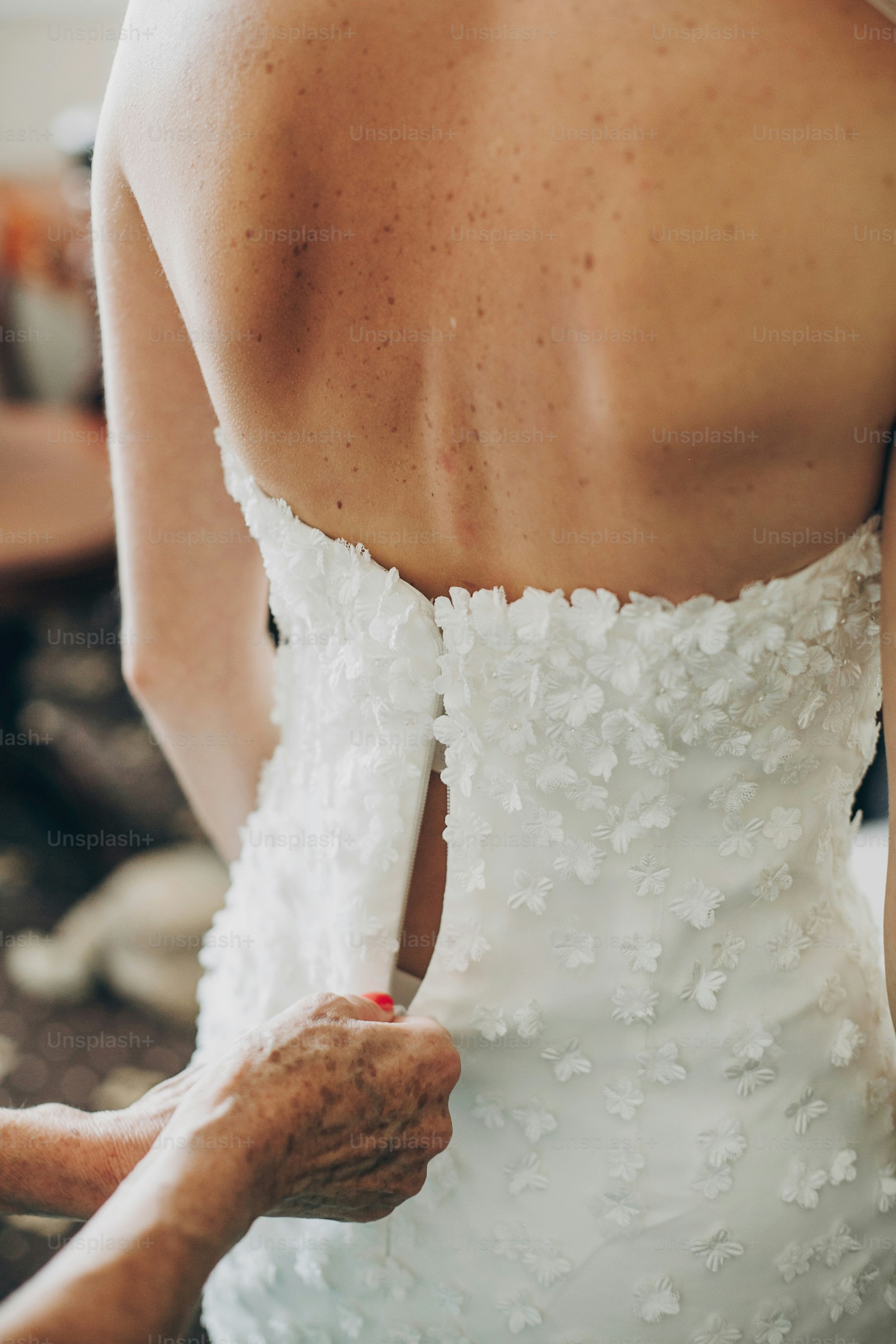 Stylish bride getting dressed in modern gown with bridesmaids and mom ...