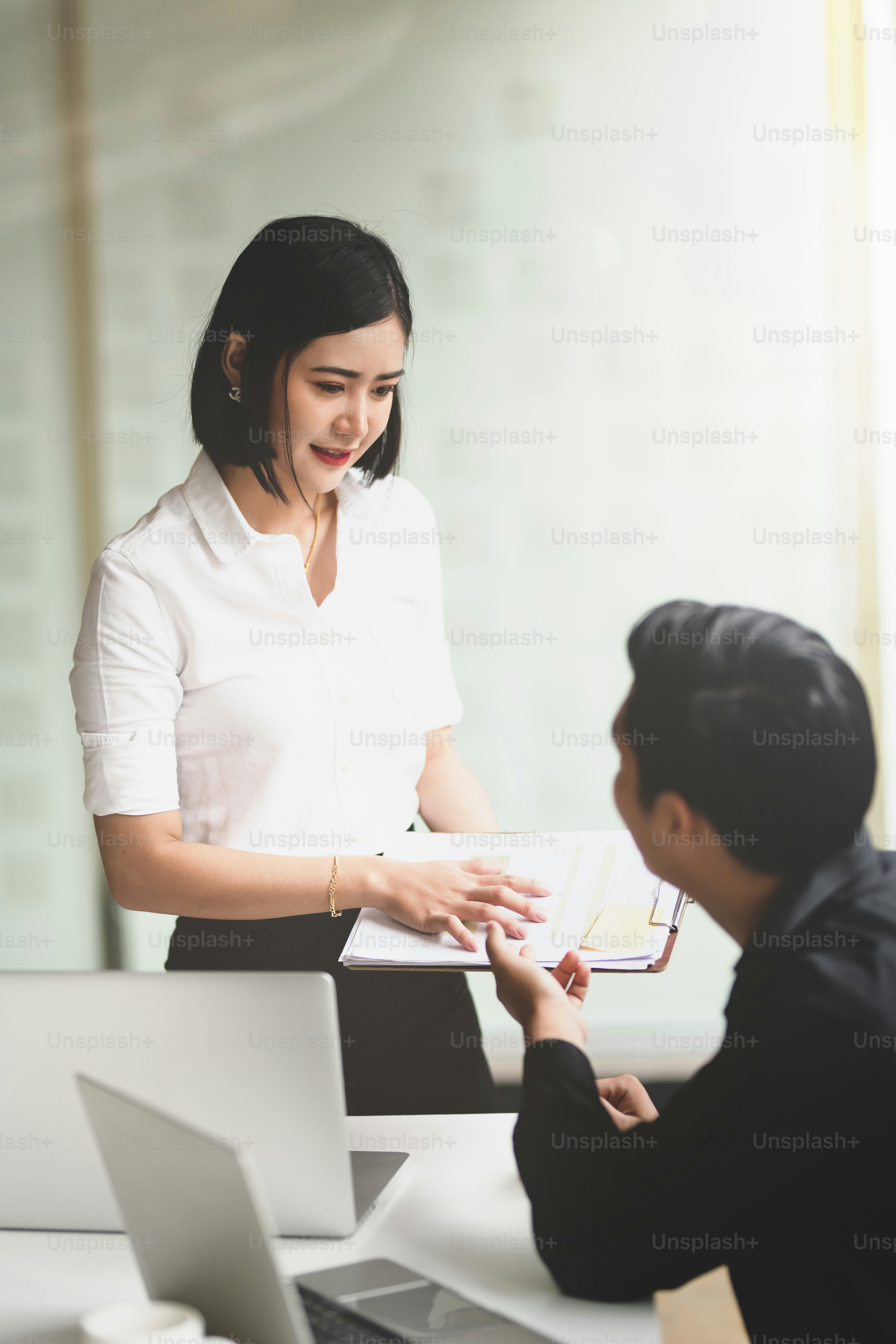 Beautiful young secretary providing new data to her boss in modern ...