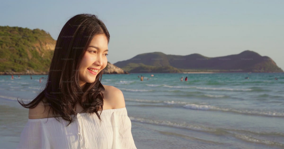 해변을 걷고 있는 젊은 아시아 여성 아름다운 여성은 저녁에 일몰 때 바다 근처 해변을 산책하며 휴식을 취합니다 라이프 스타일