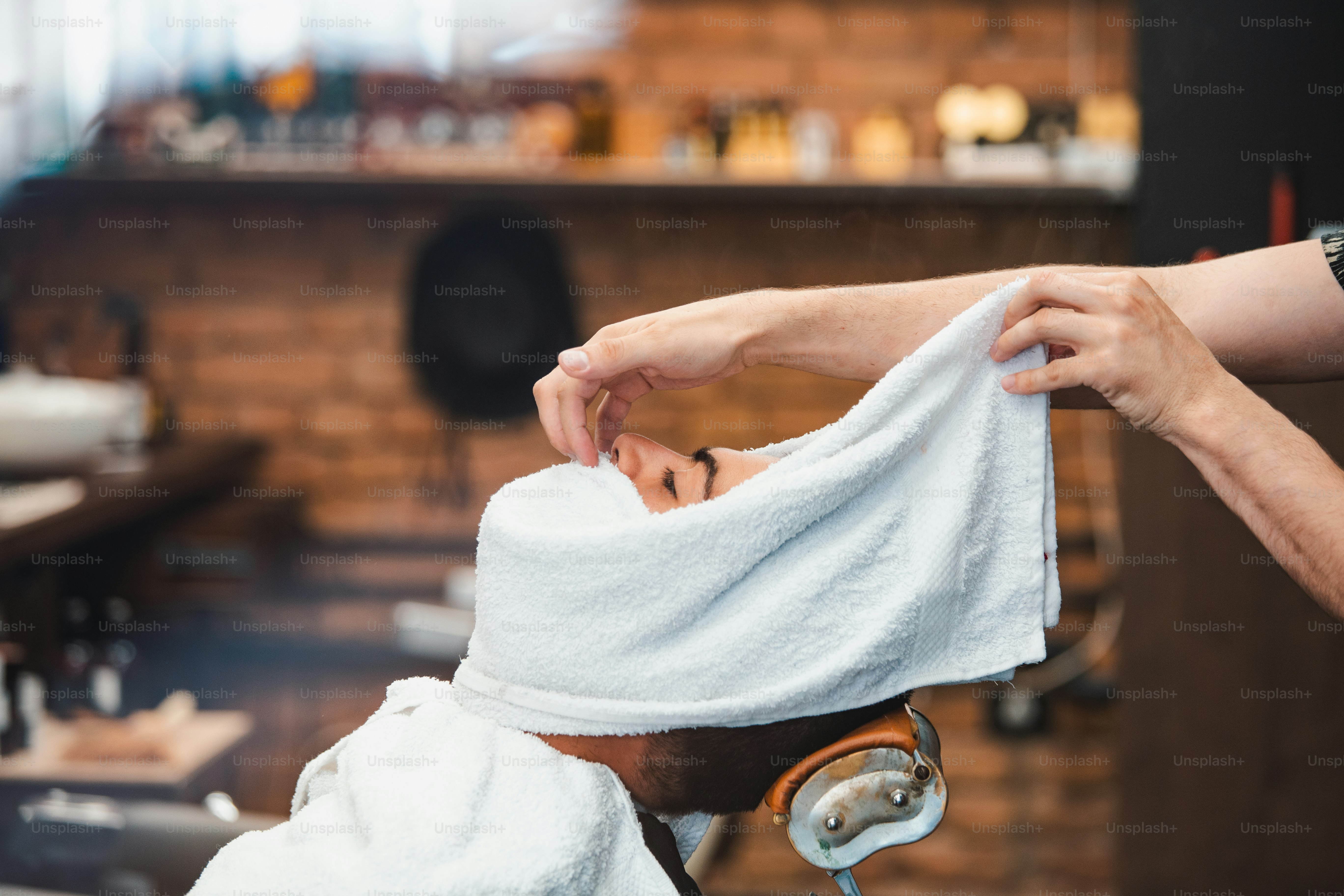 Barber covers the face of a man with a hot towel. Traditional ritual of ...