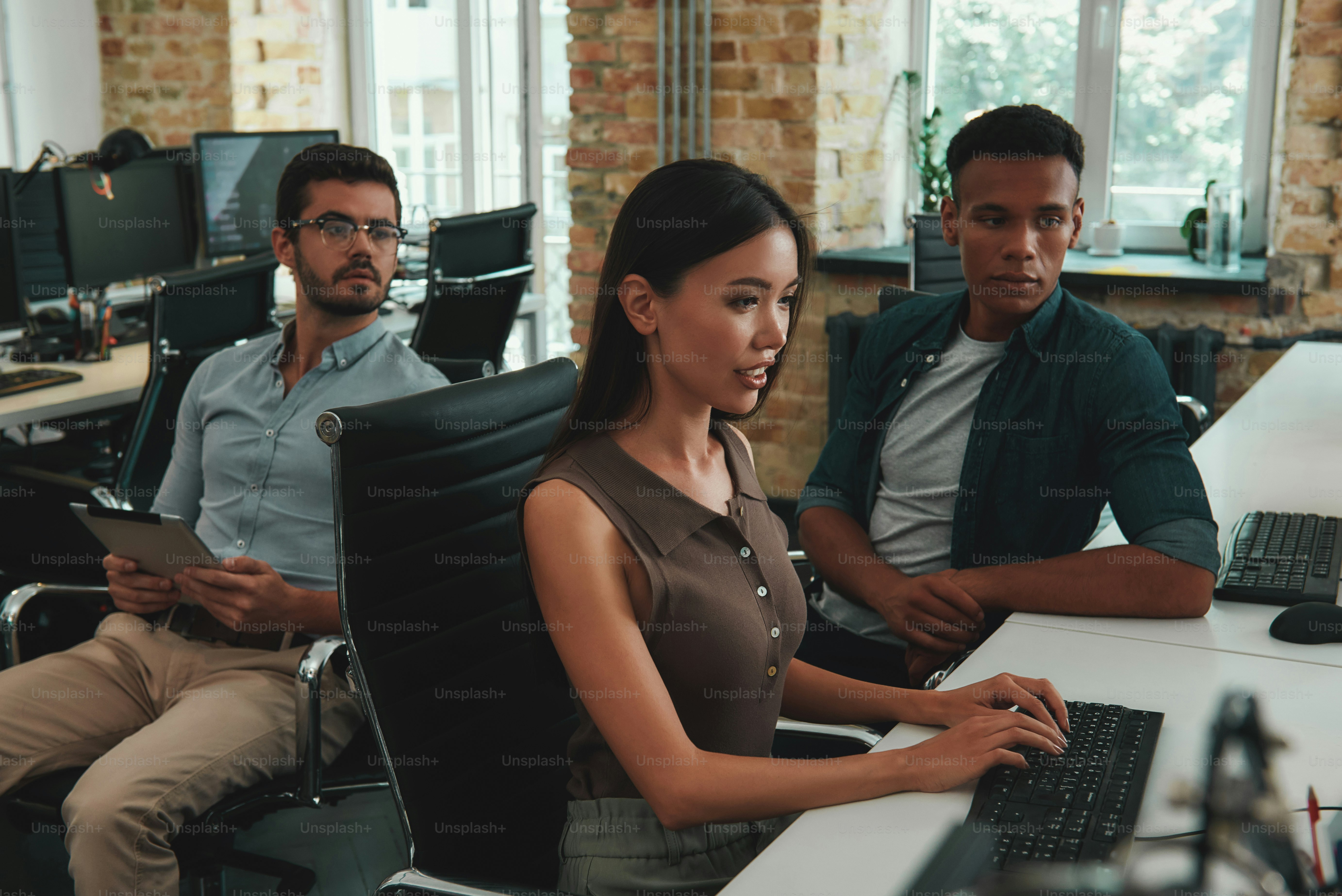 Quick meeting. Group of cheerful young employees working on computers ...