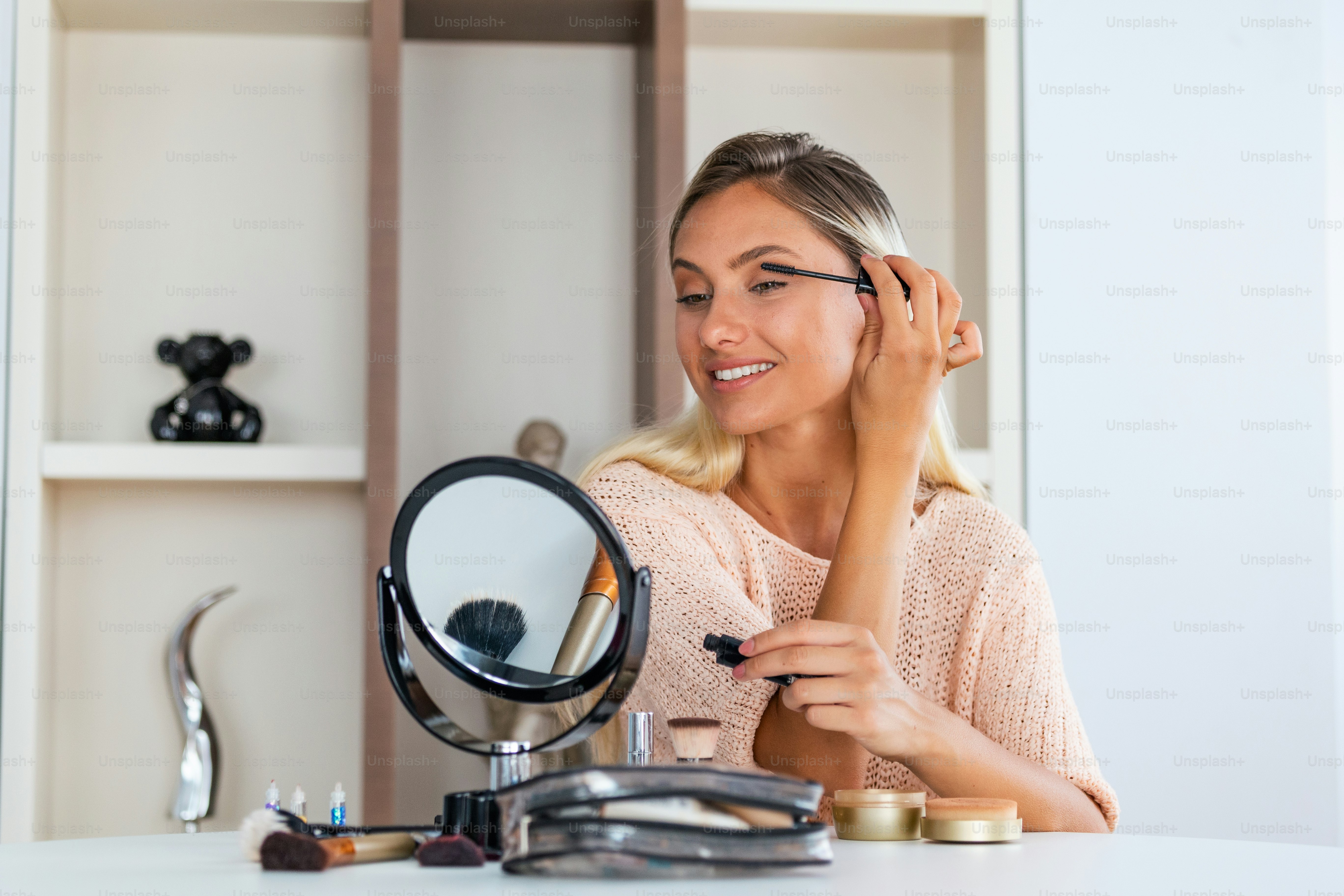 Brunette woman applying make up (paint her eyelashes) for a evening ...