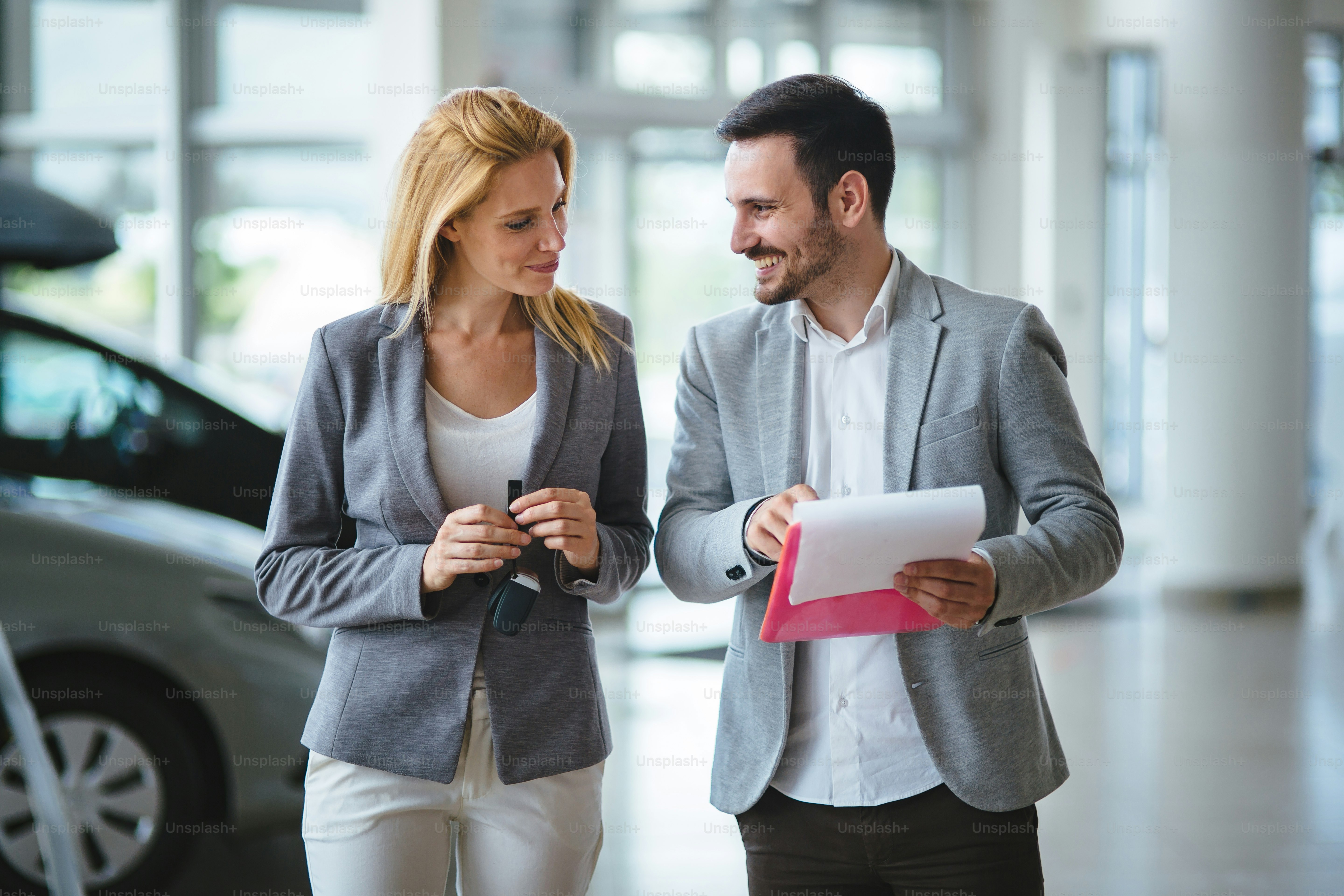 Woman is talking to handsome car dealership worker while choosing a car ...