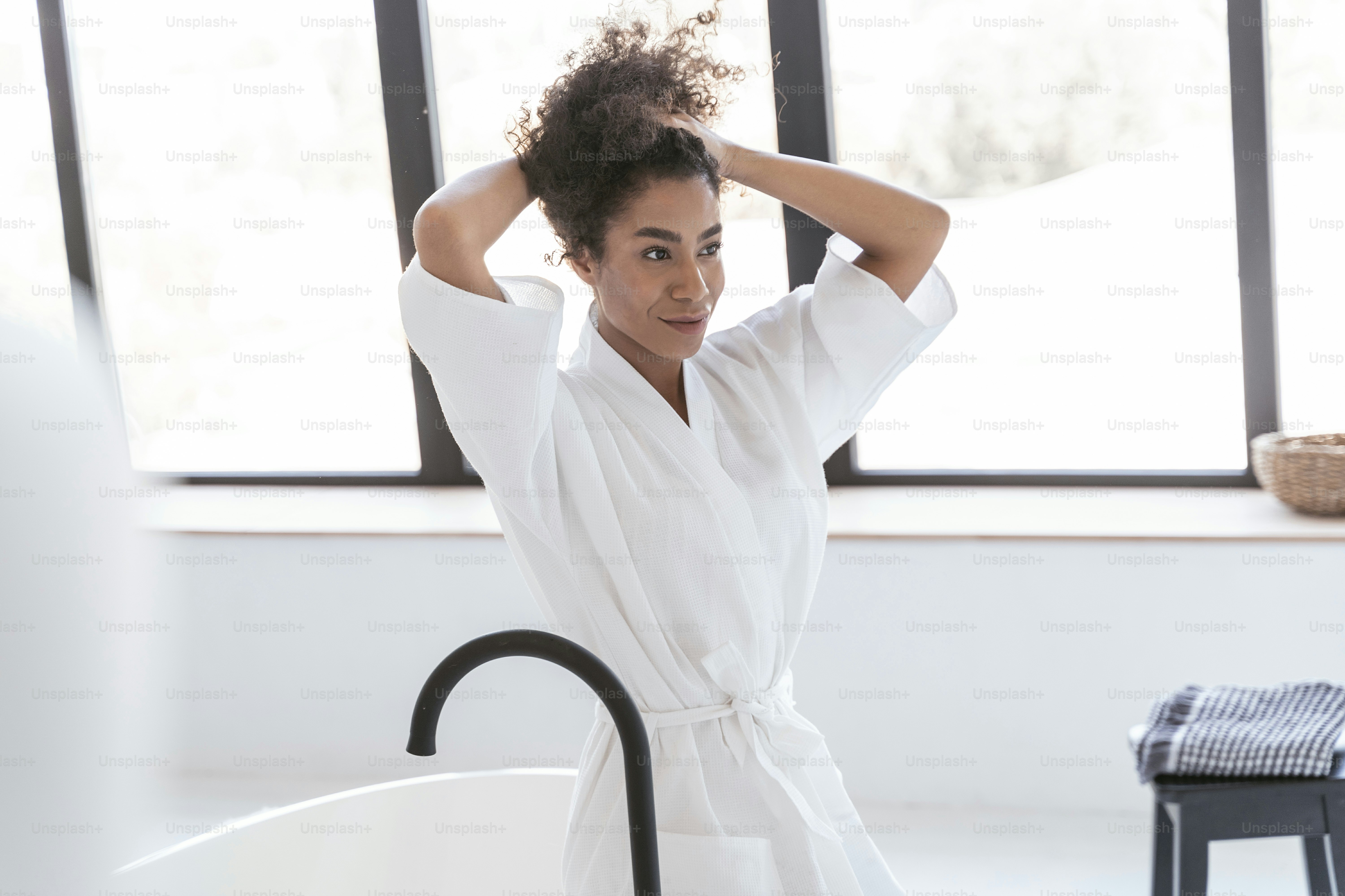Good-looking young lady clumping her hair before the bathing photo ...