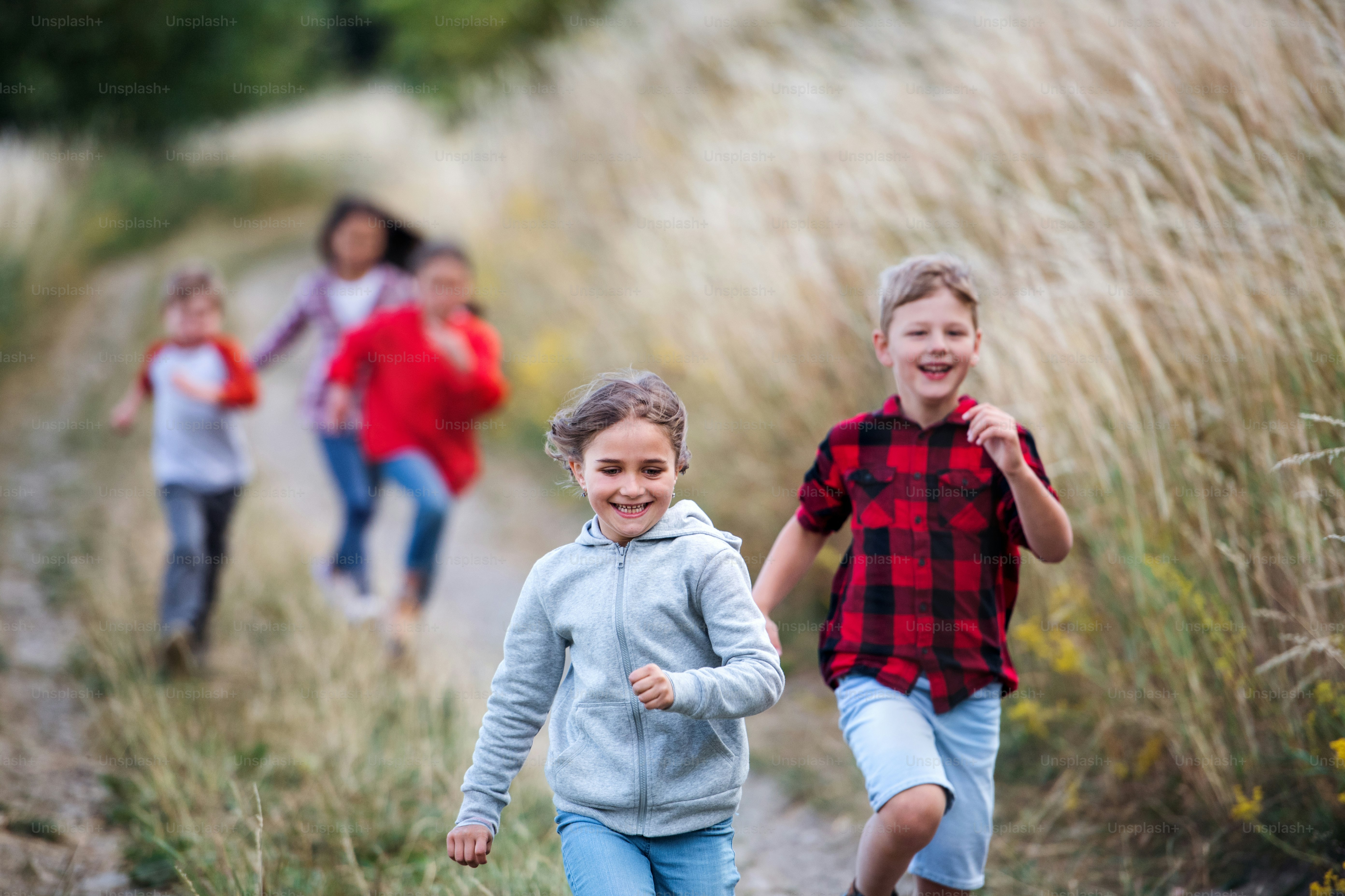 Portrait of group of school children running on field trip in nature ...