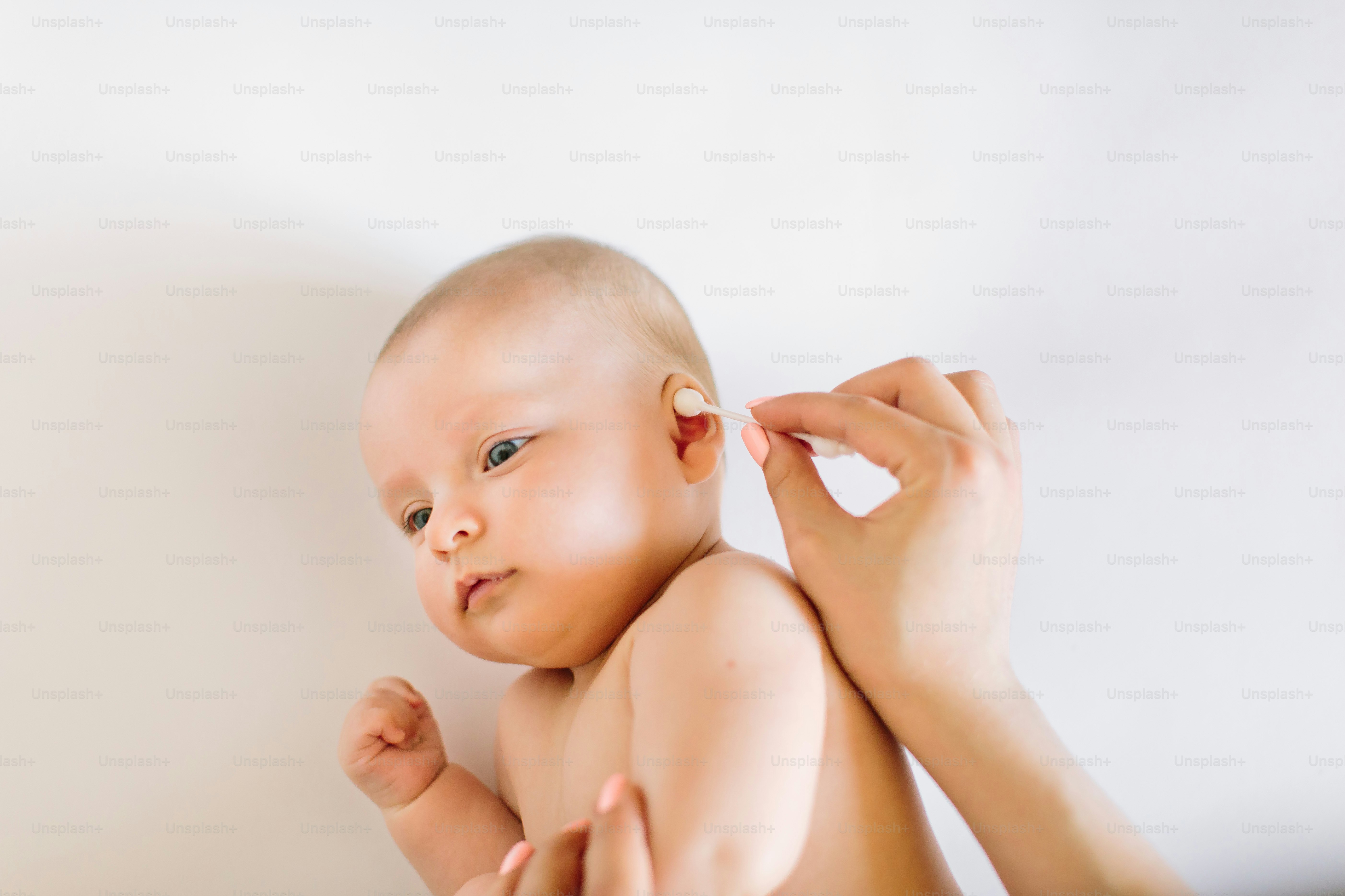 Foto La mano de la madre limpia la oreja del bebé con un hisopo de ...