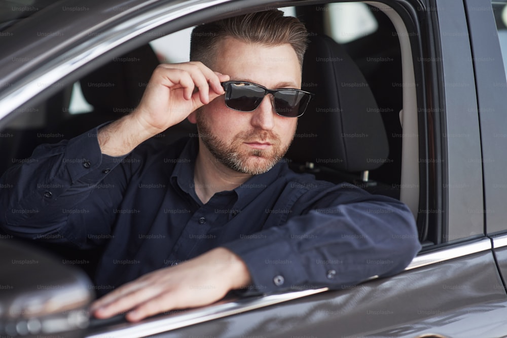 Foto Aspecto elegante. Hombre con ropa oficial probando su nuevo coche ... Foto Aspecto elegante. Hombre con ropa oficial probando su nuevo coche ...