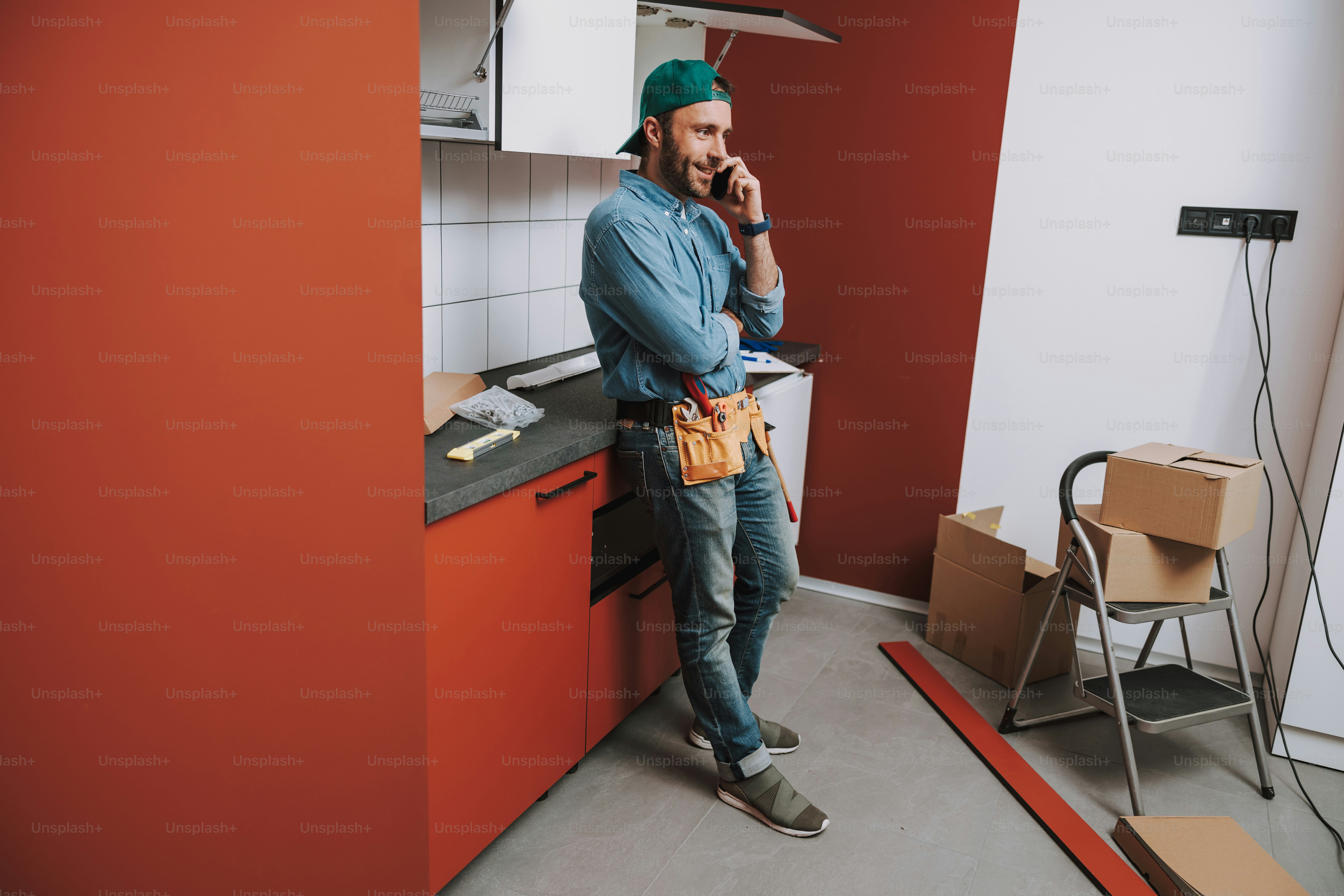 Calm young handyman repairing his kitchen stock photo photo – Jeans ...