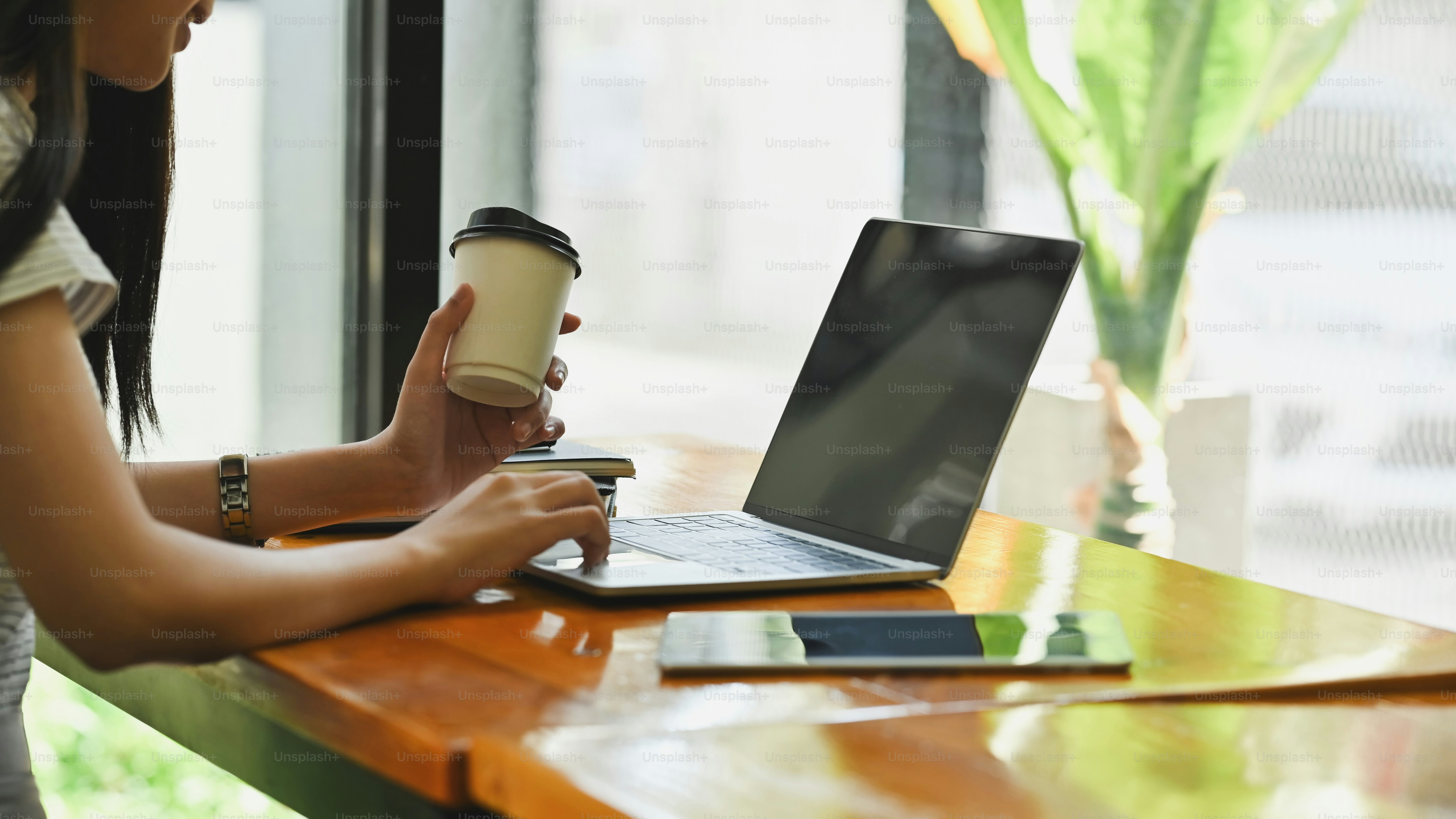 Cropped shot female using laptop and holding coffee paper cup. photo ...