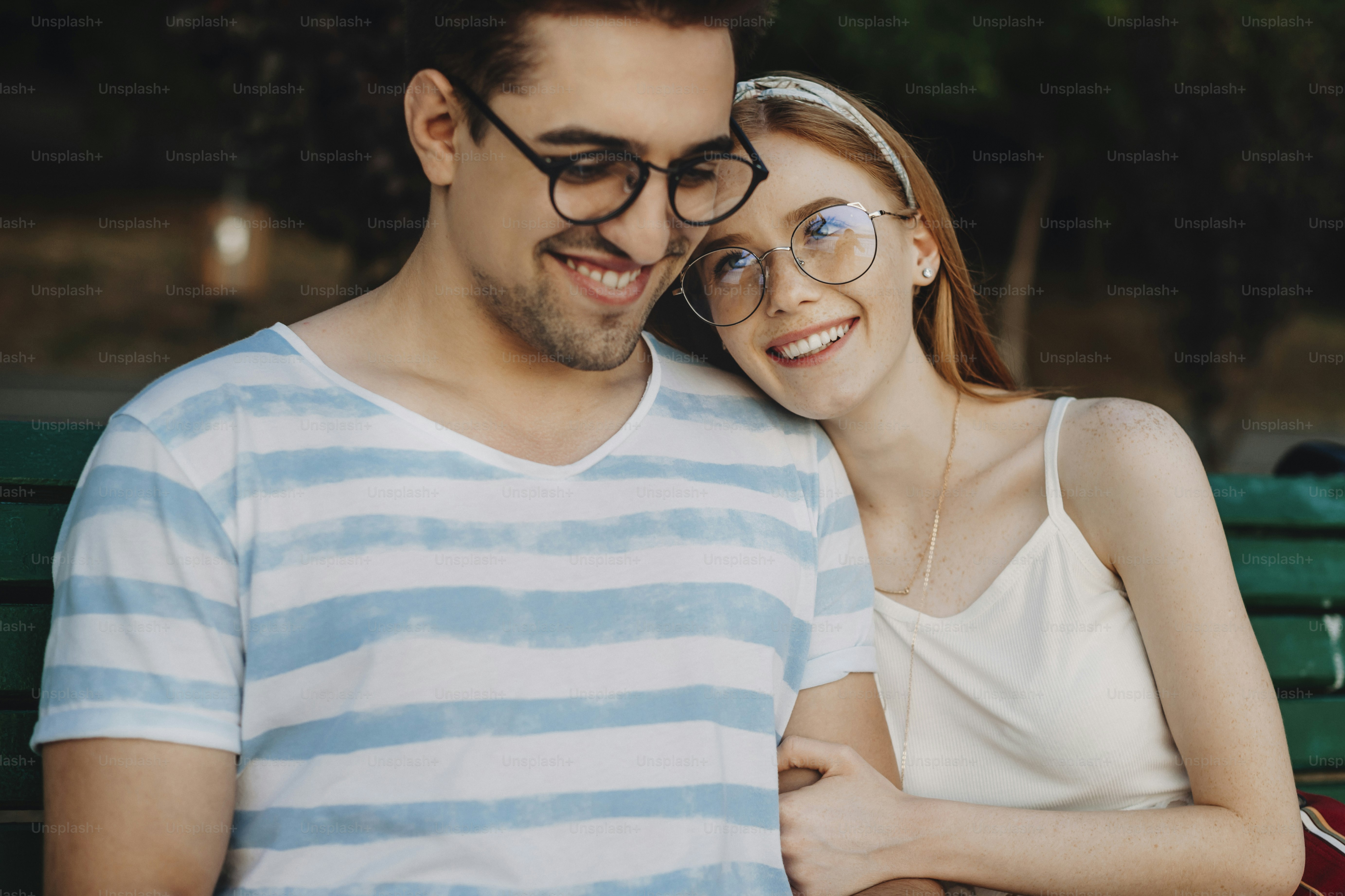Portrait of a beautiful couple embracing while sitting on a bench ...