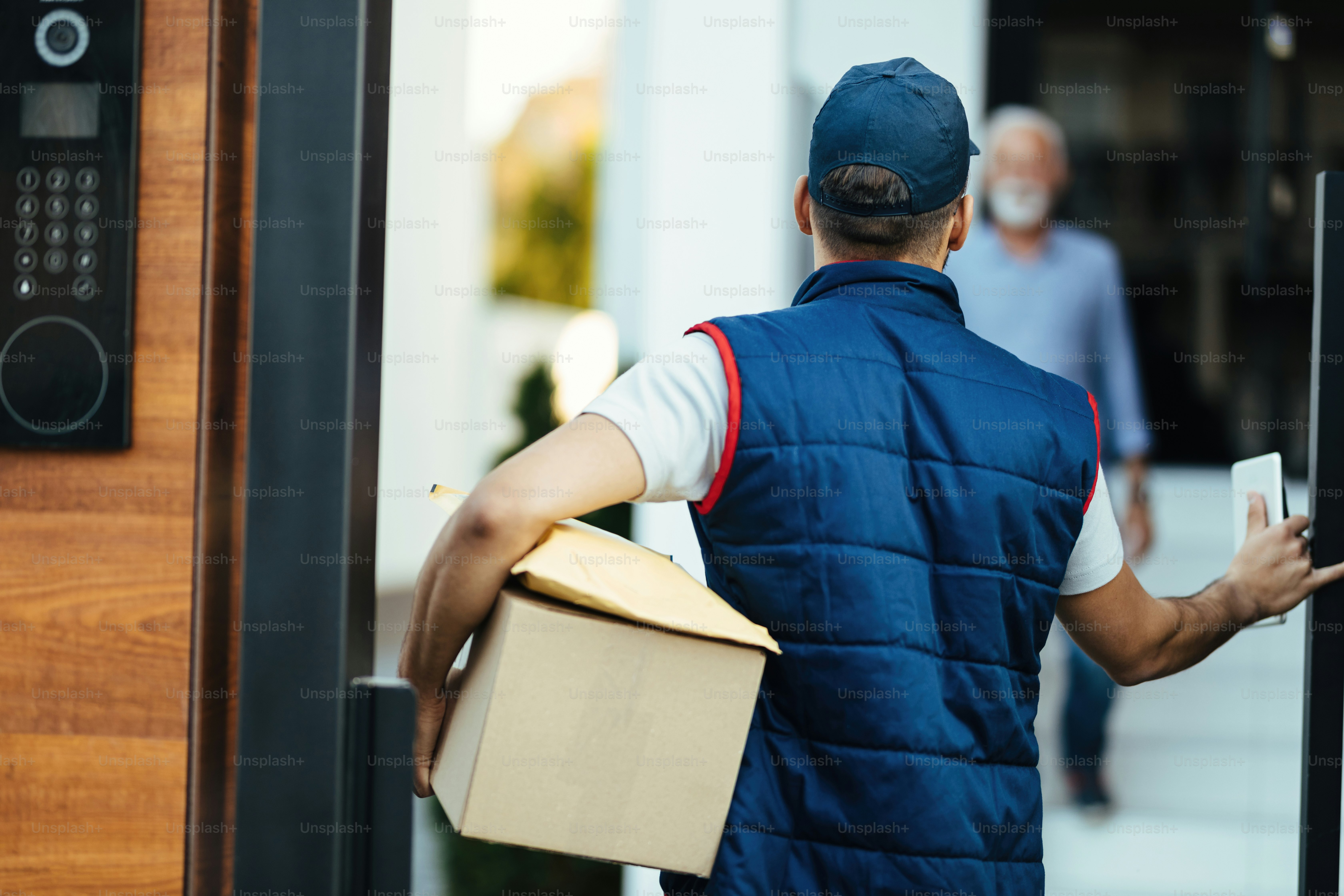 Rear view of courier delivering packages to customer's home. photo ...