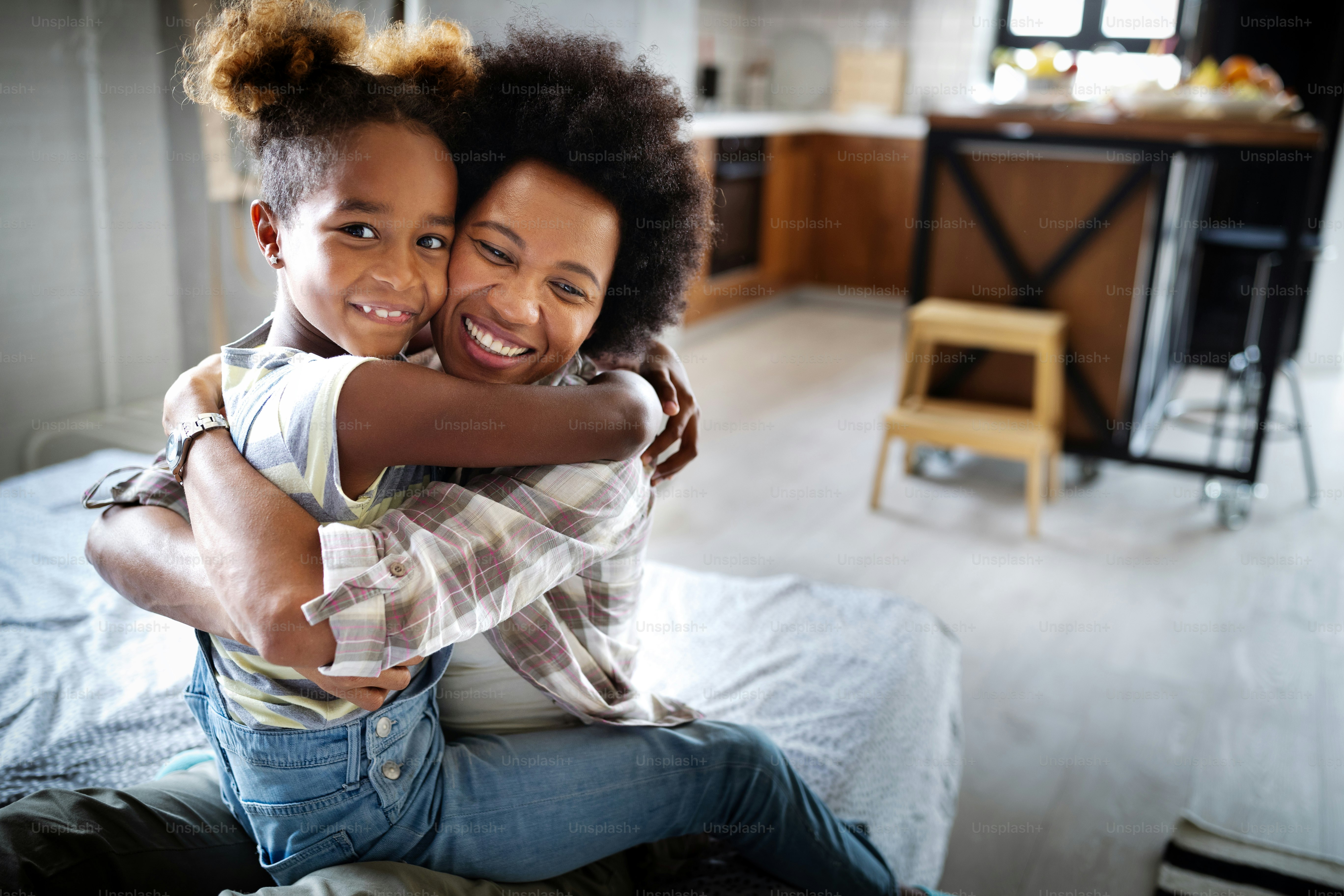 Happy african mother playing, having fun, hugging with her daughter at ...