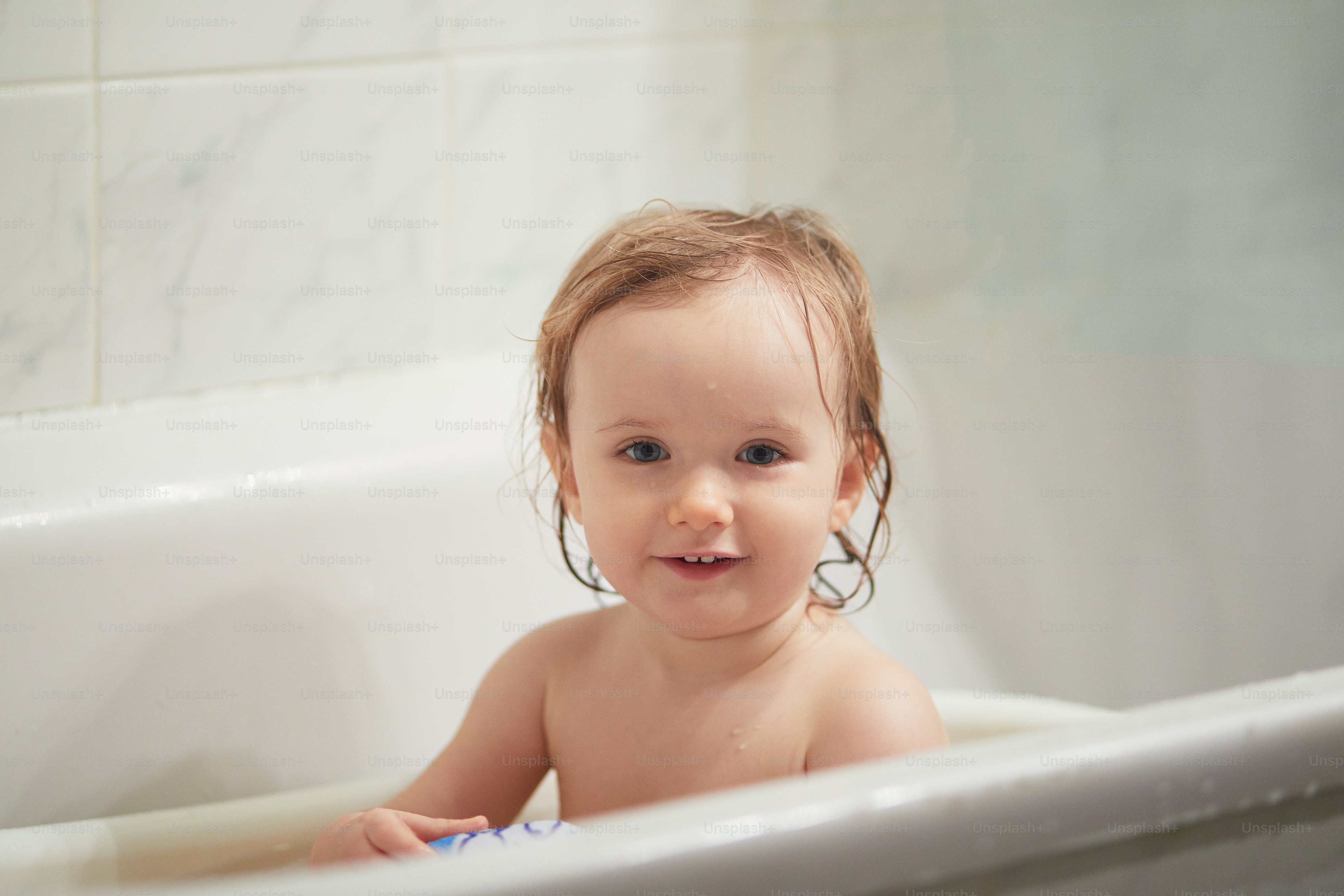 Cute little girl playing with rubber toys in small bathtub. Happy kid ...