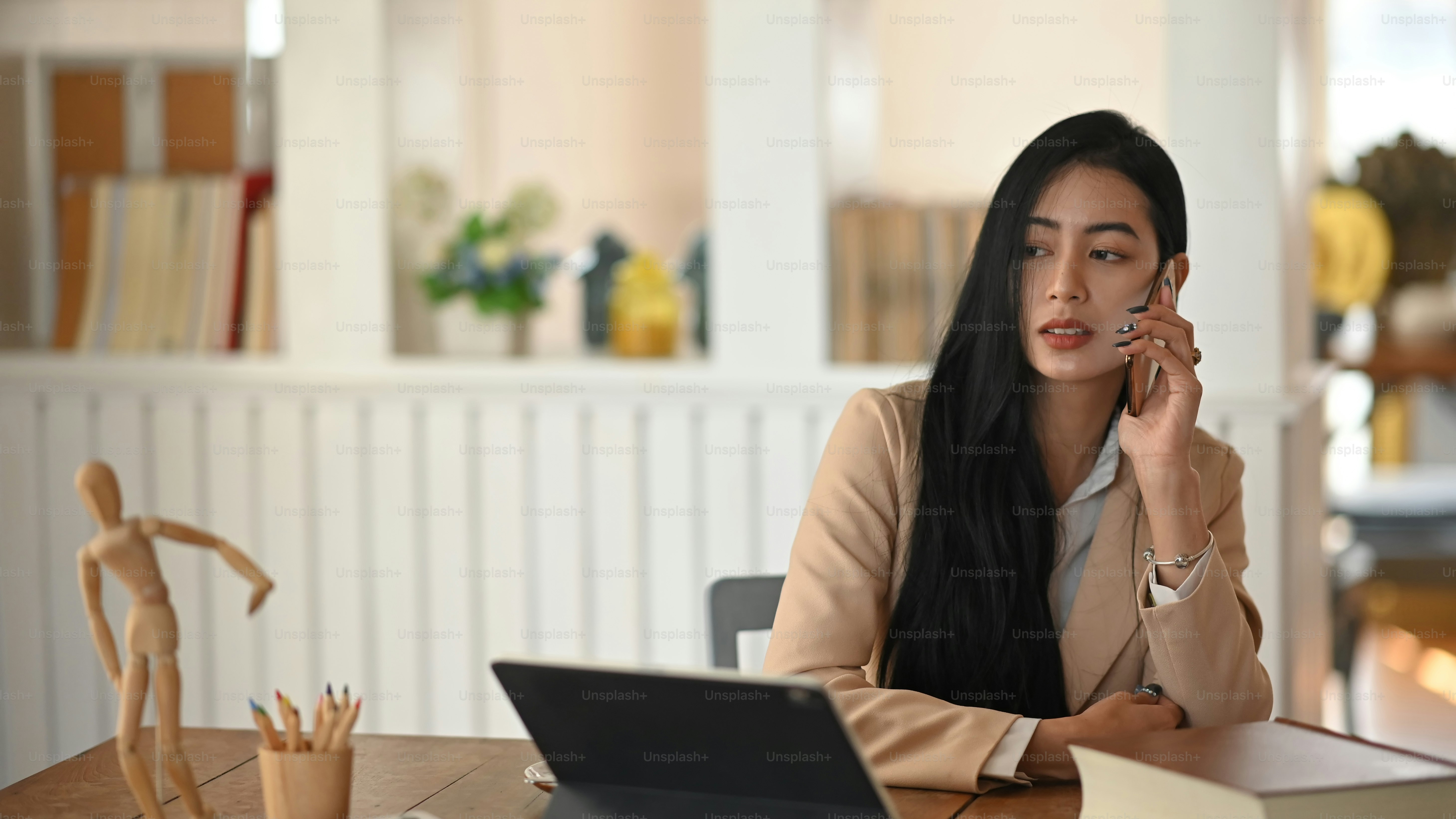 Young woman calling on cell phone in creative work desk. photo ...