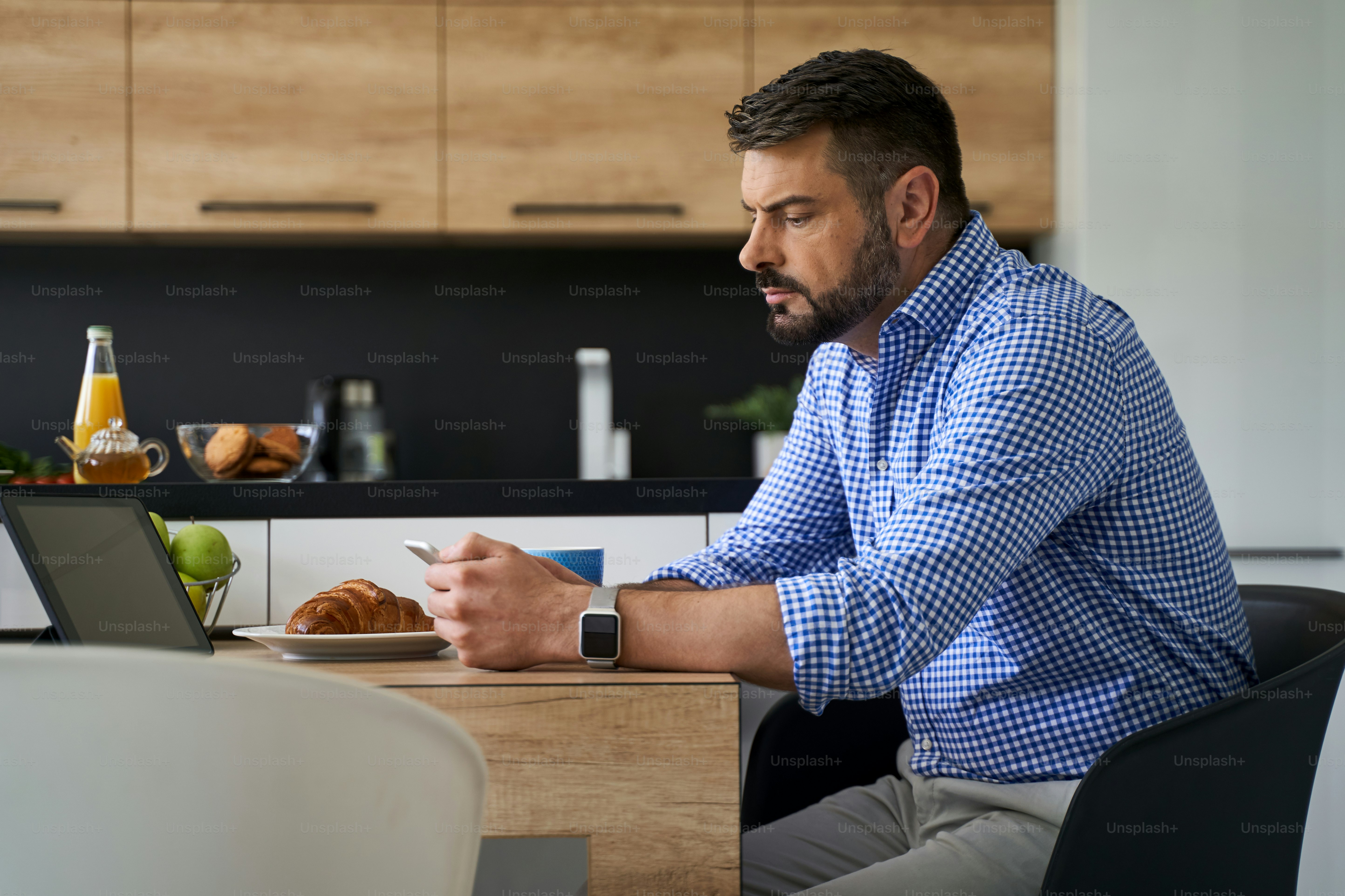 Bearded male using smartphone during breakfast photo – Croissant Image ...