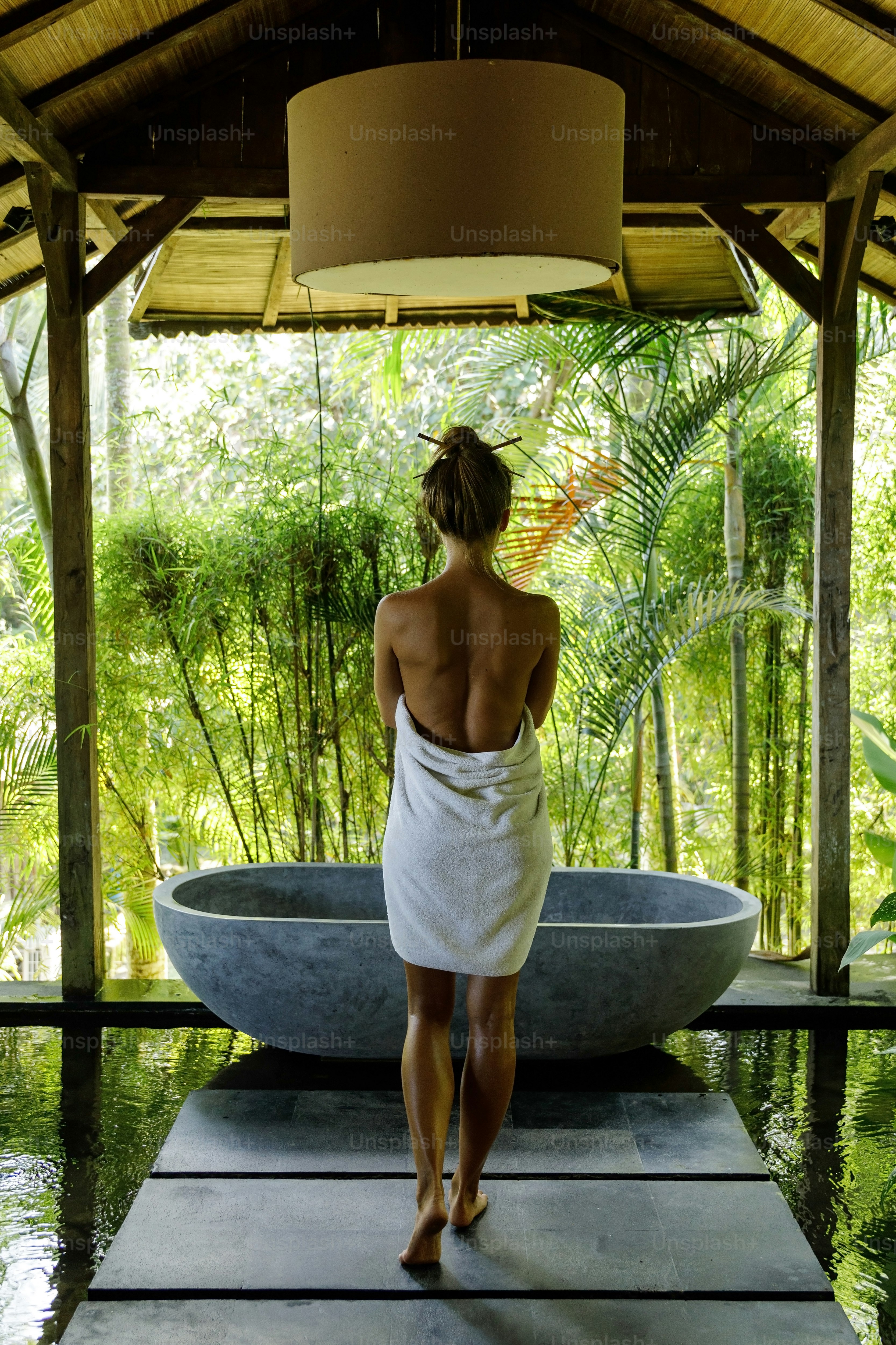 Woman in open air bathroom with stone bath in Balinese style photo ...