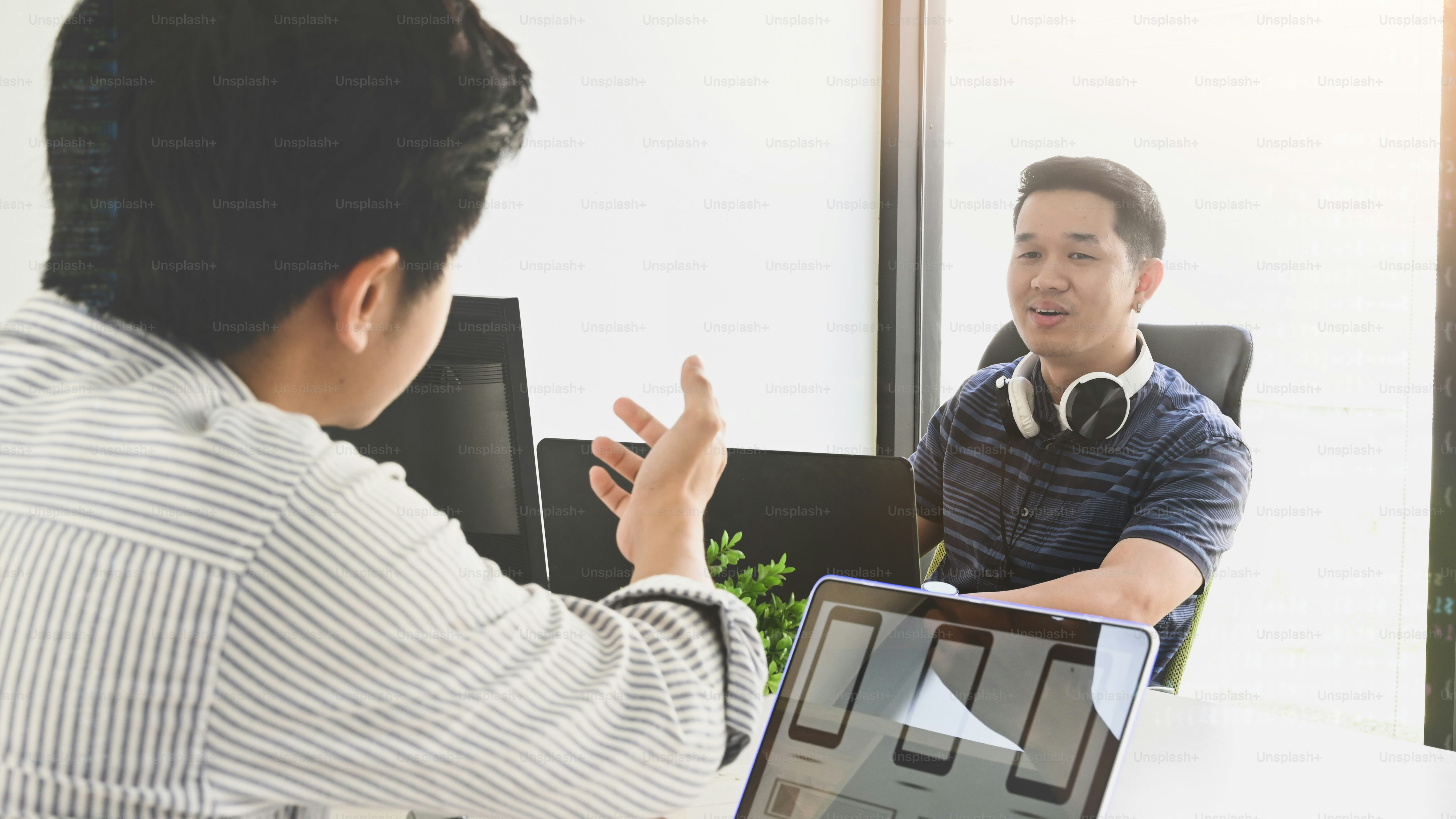 Photo of young programmer while talking/planning with his teammate ...