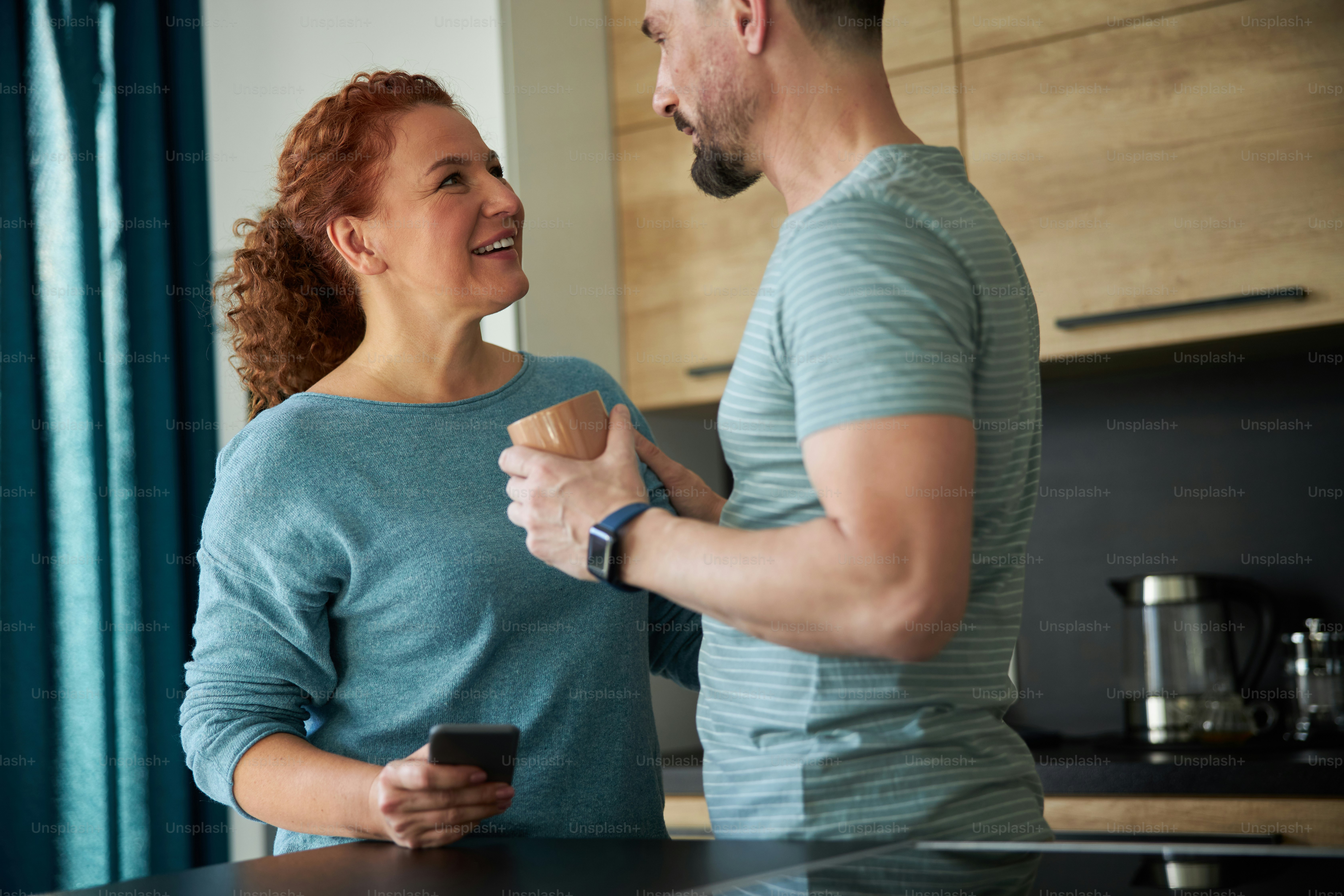 Caring couple is communicating at table while drinking tea and using ...