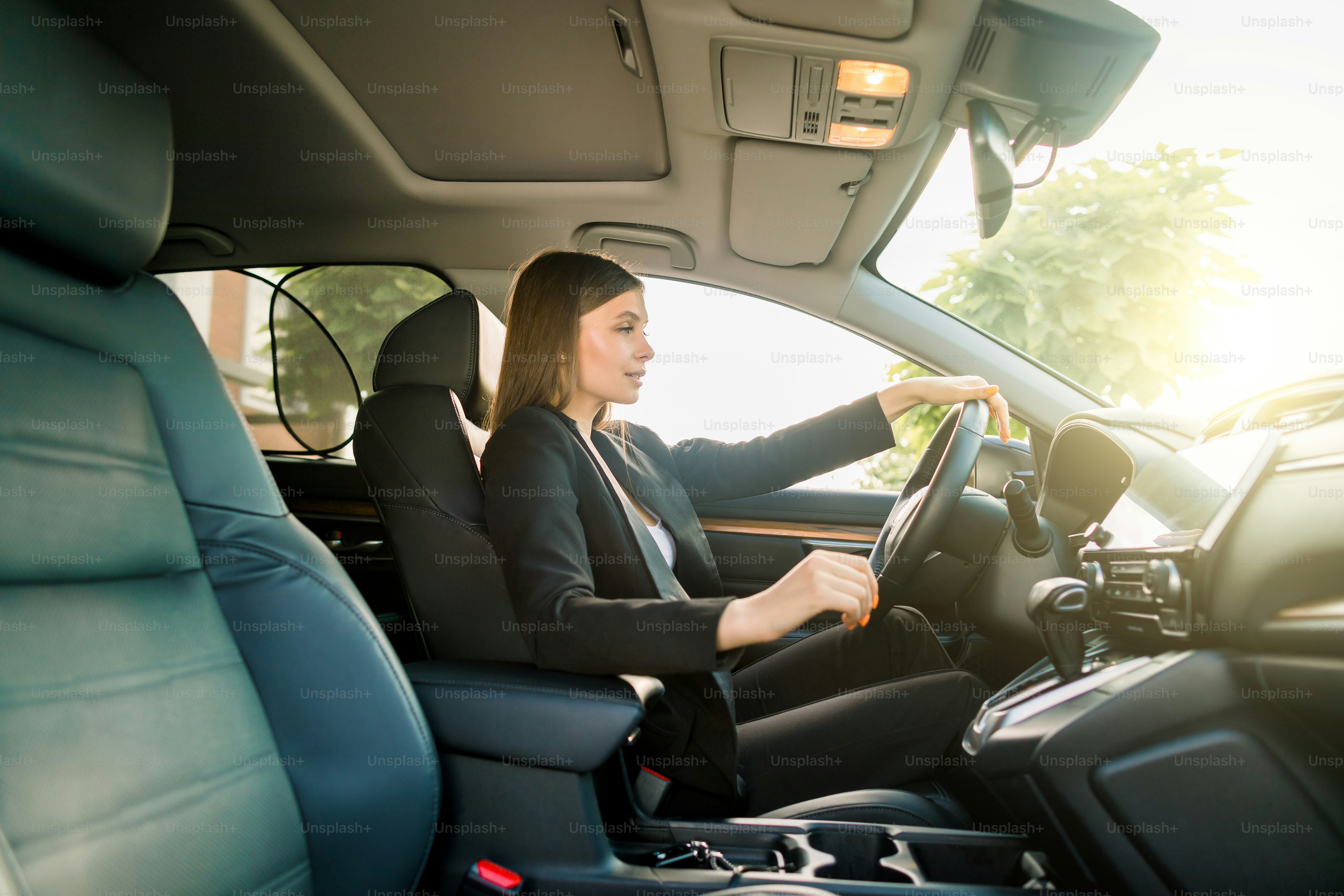 Driving around city. Young attractive business woman in black suit ...