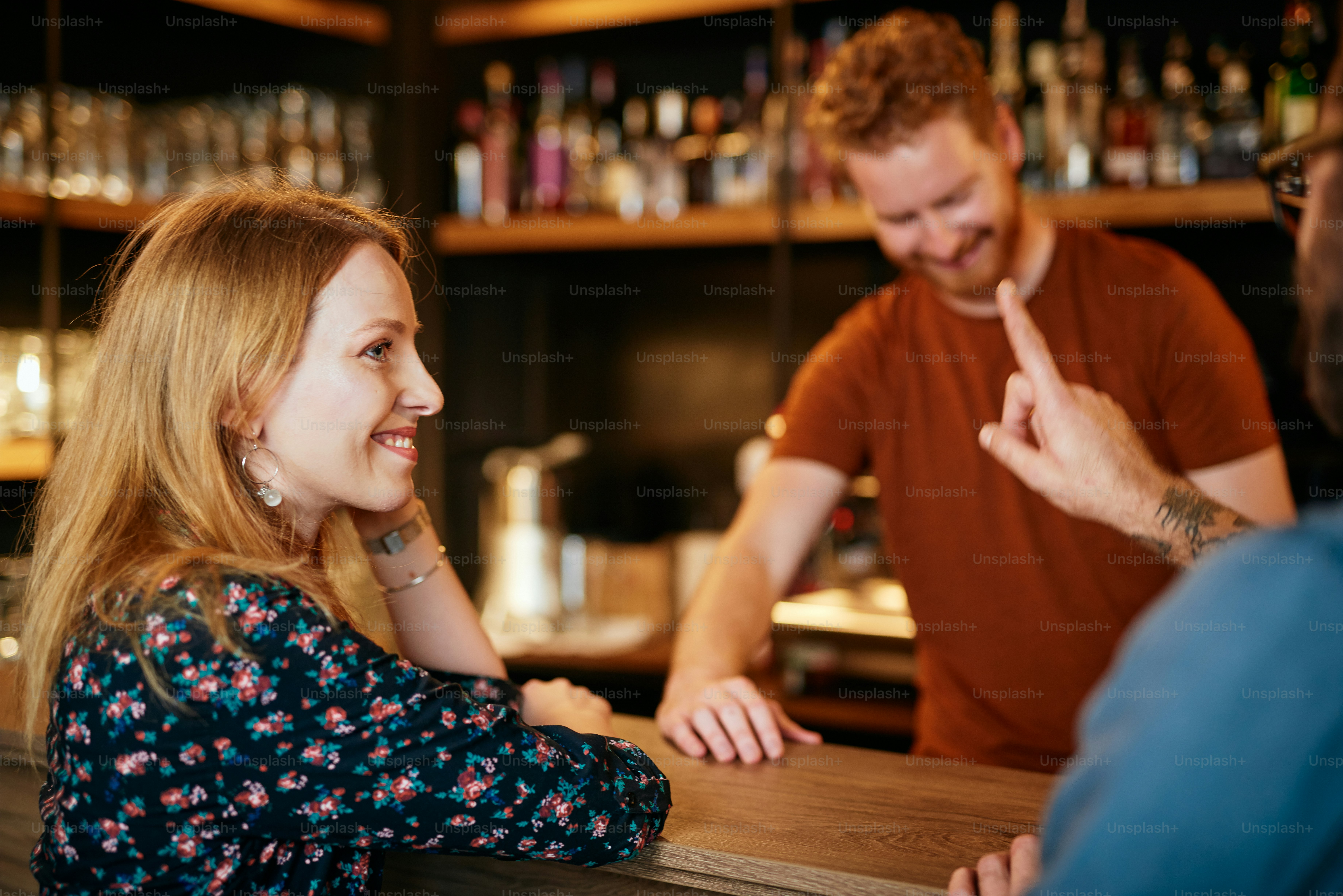 Couple sitting at bar counter and enjoying friday night. Man ordering ...