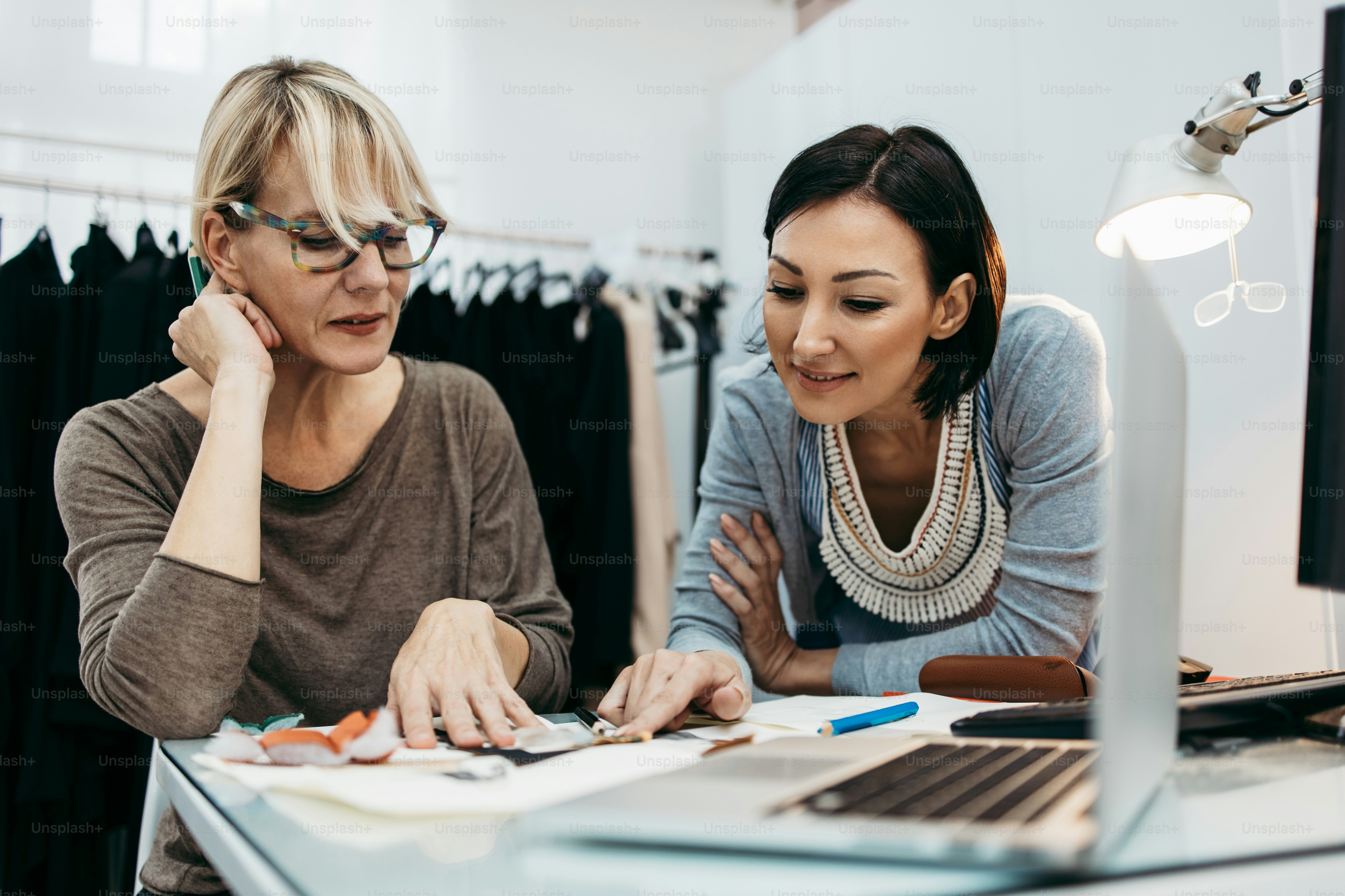 Two professional designers working in fashion studio. Creative people ...